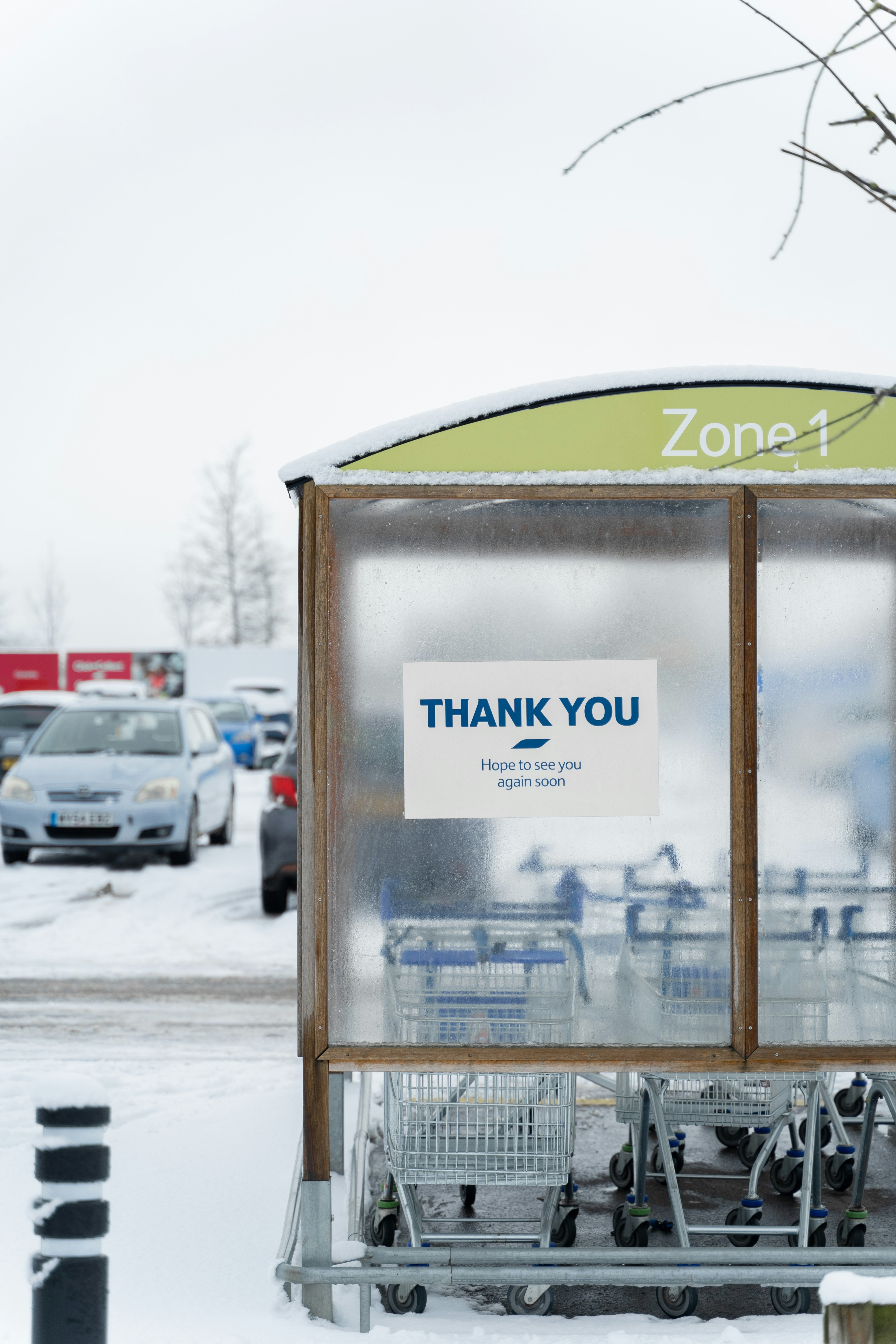 Thank You in Frost: A Glass Shelter Framed by Snow-Covered Cars