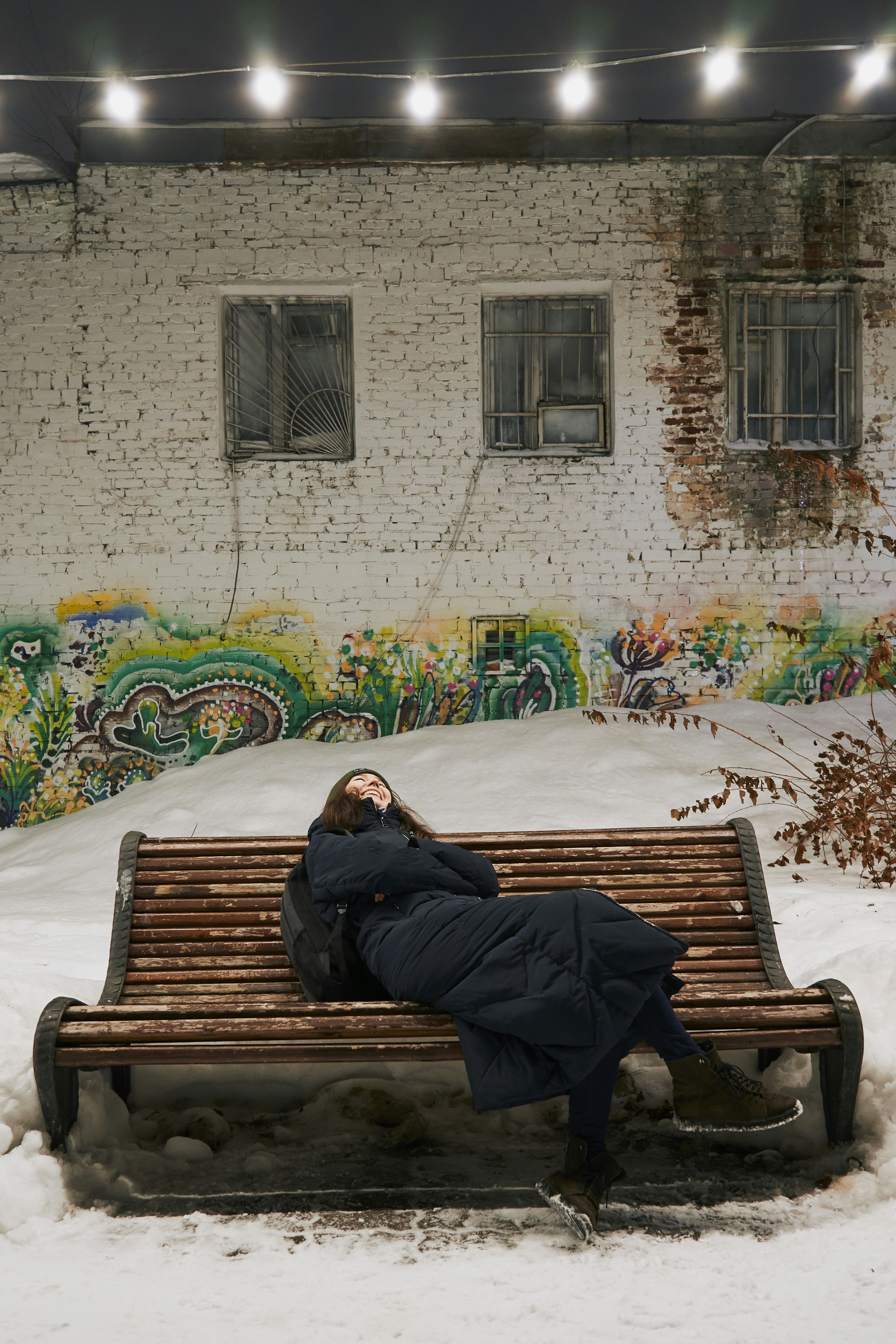 man in black jacket sitting on brown wooden bench