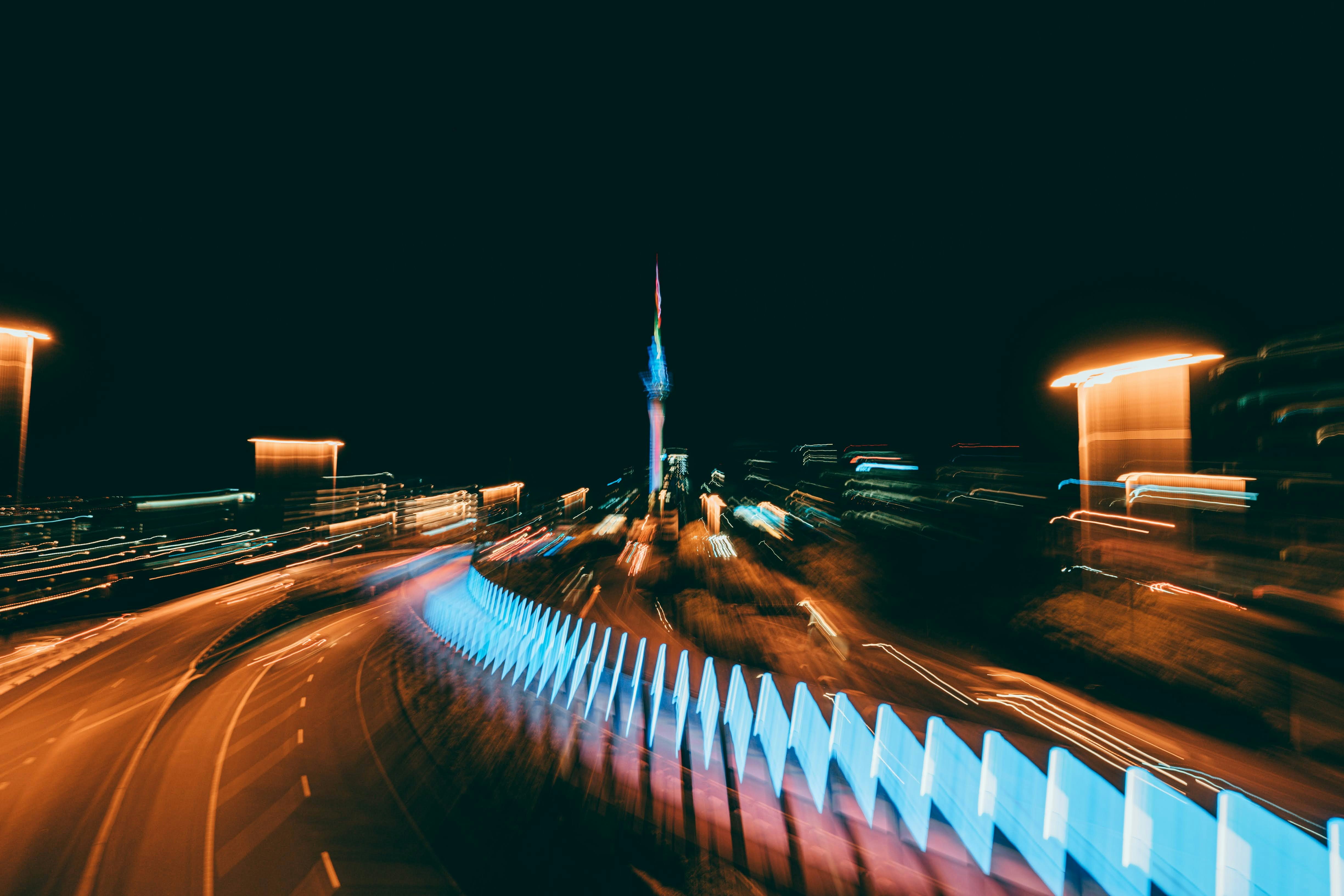 Long exposure of a city road at night with vibrant blue lights and motion trails.