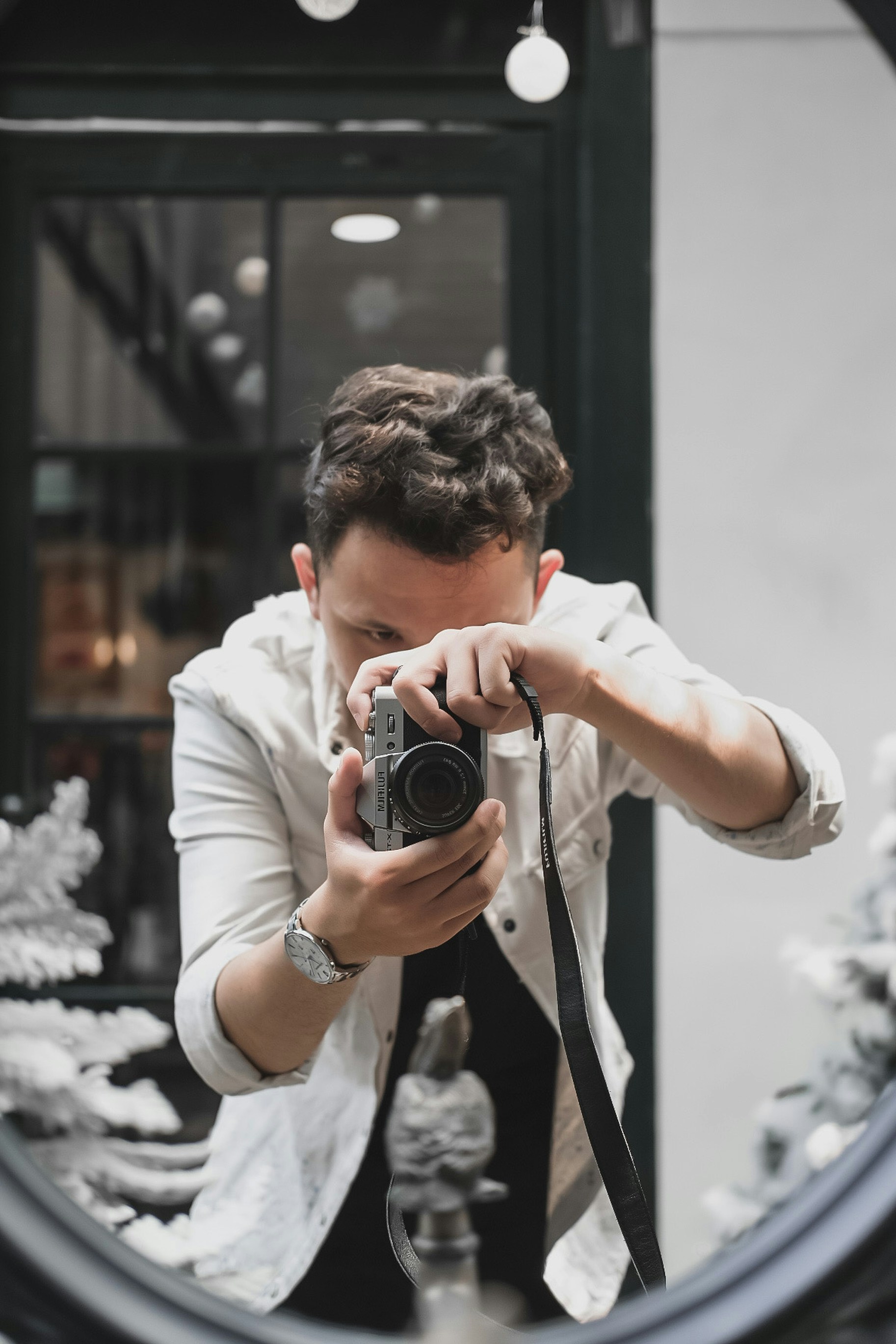 Lens in Focus: A Handheld Portrait Reflected in a Circular Storefront Mirror