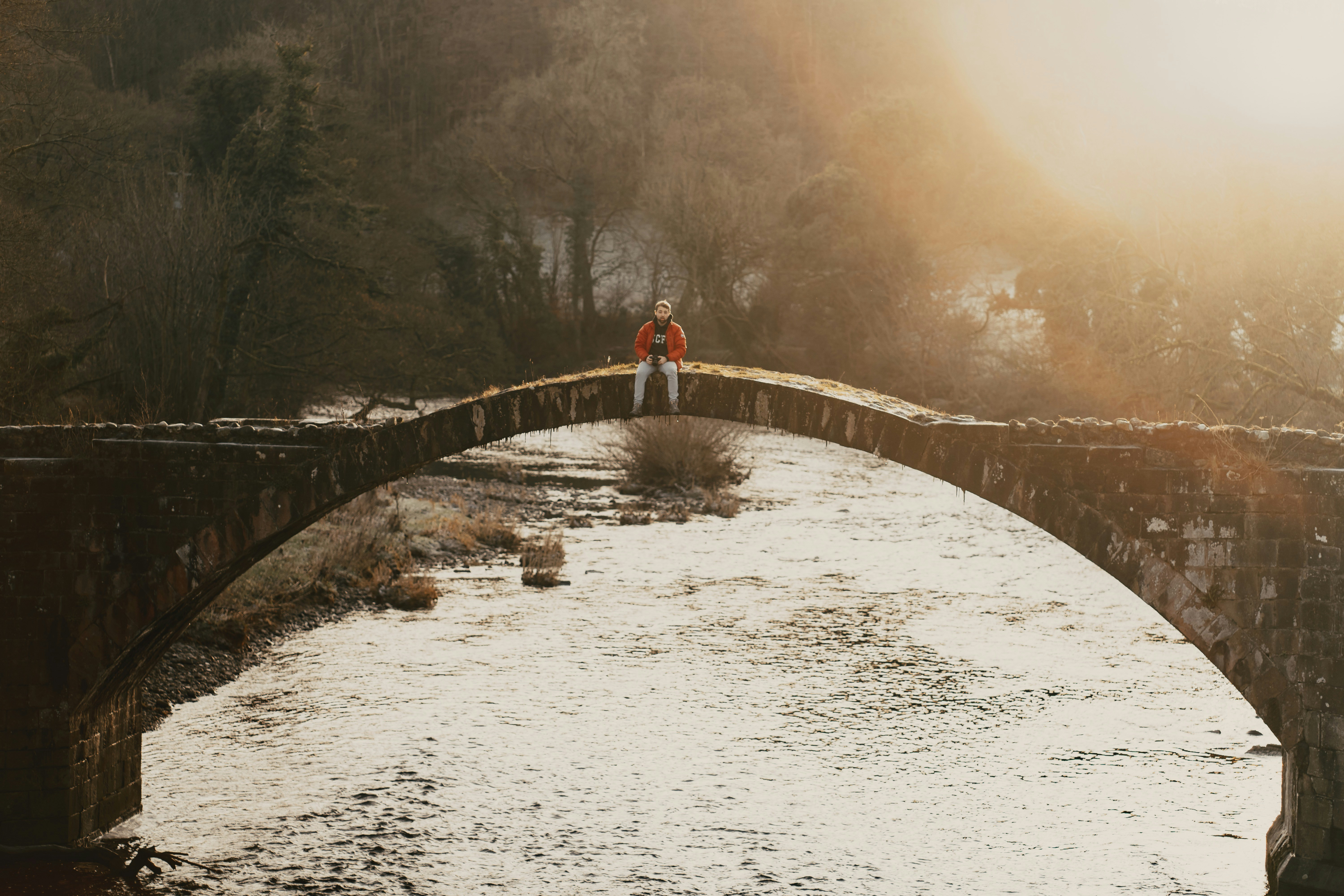 Bridge Sentinel: A solitary figure on the arch under autumn light