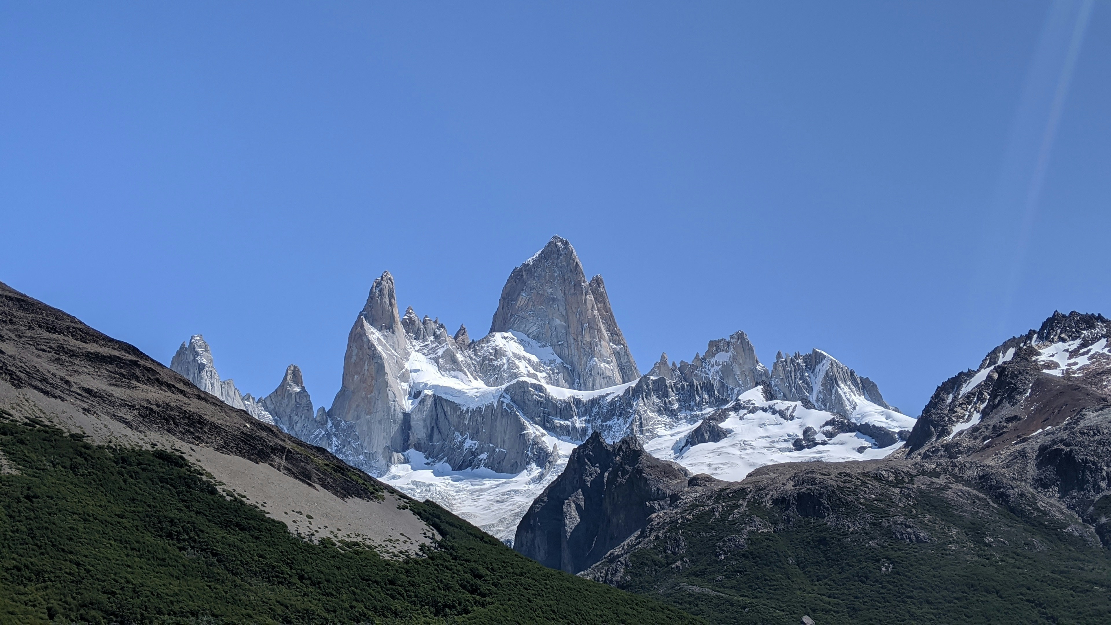 Snow-capped mountains towering against a clear blue sky, showcasing the rugged beauty of Patagonia's landscape.