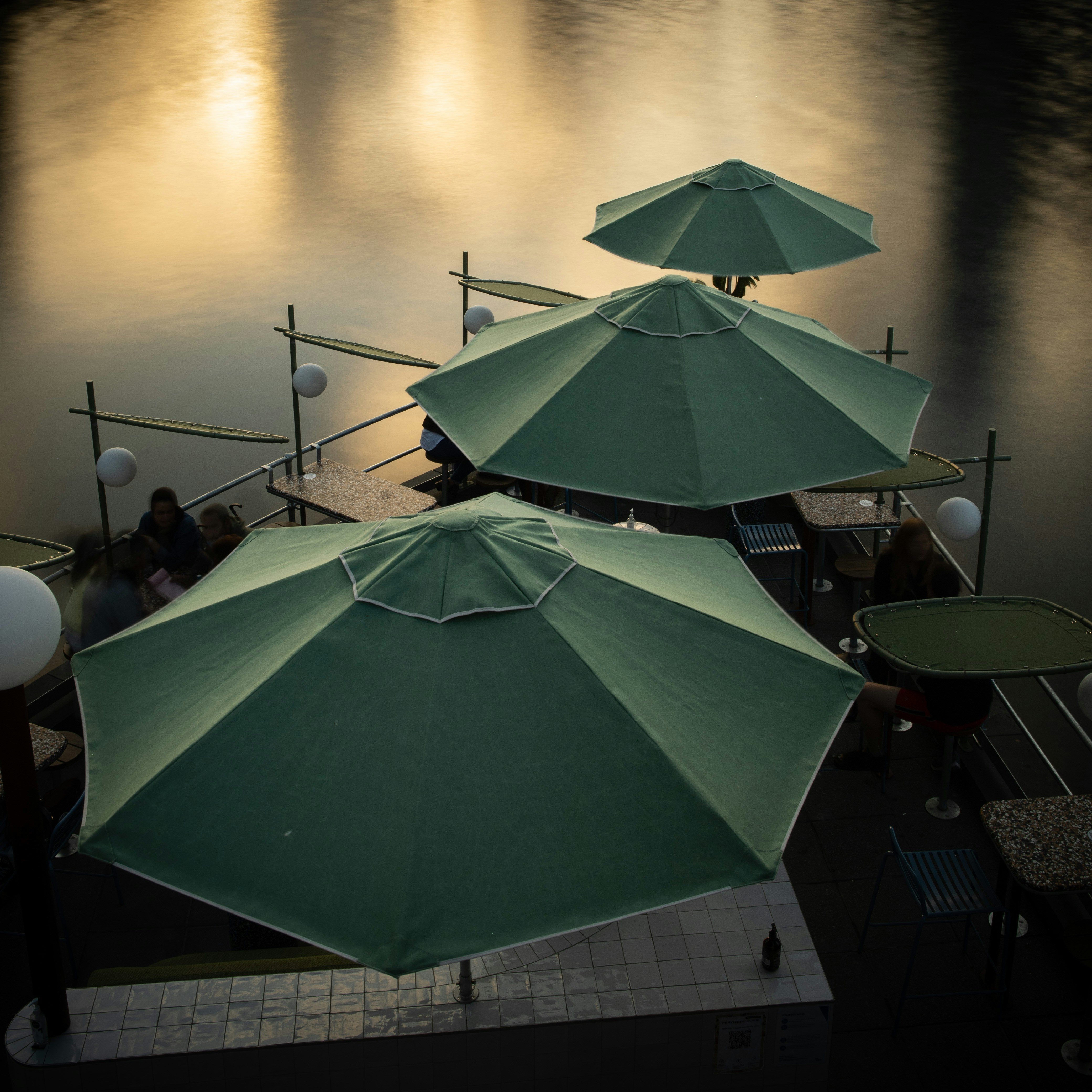 Evening Terrace: Green Parasols Overlooking a Calm Waterfront