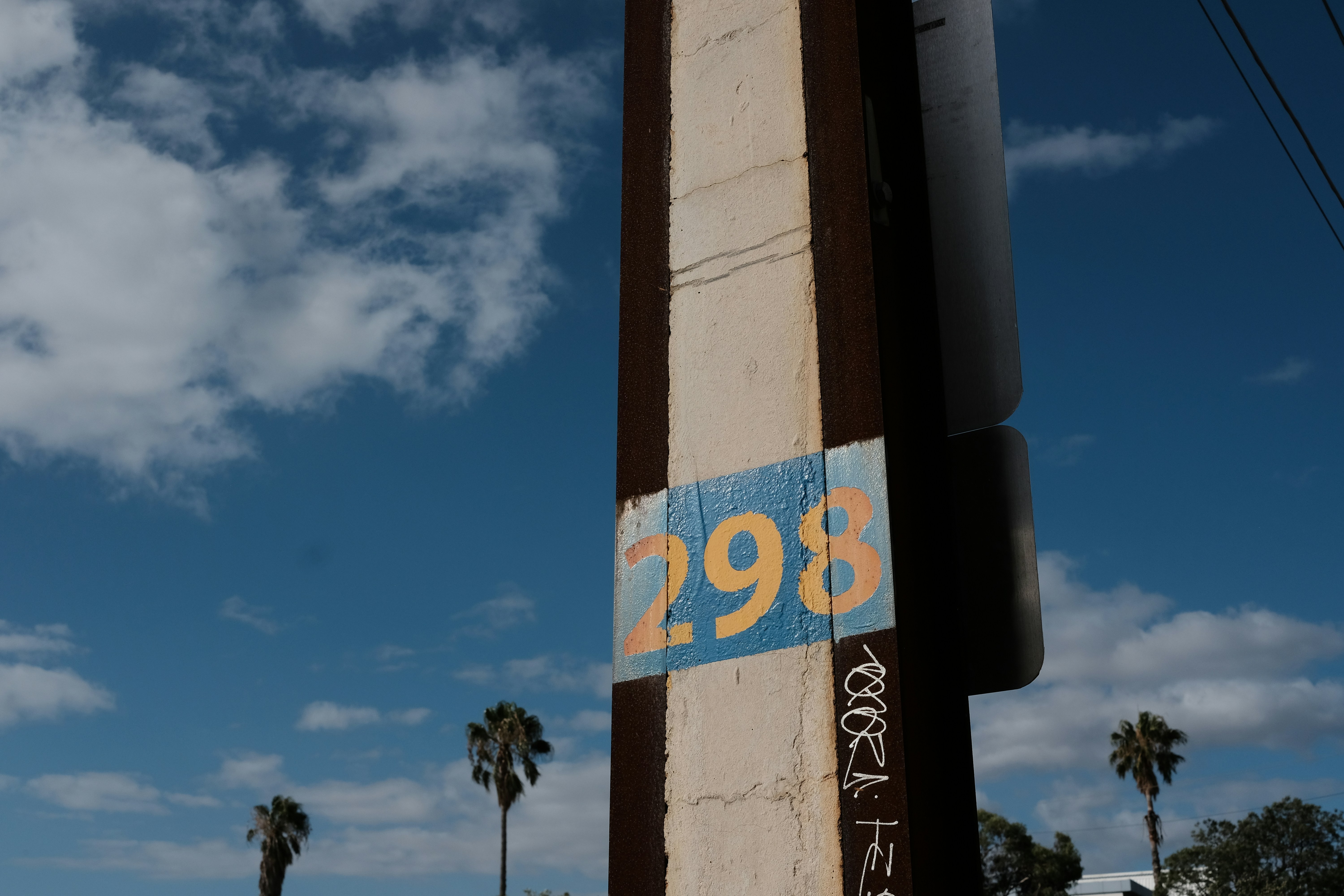 Utility pole with number 298 against a clear sky and scattered clouds.