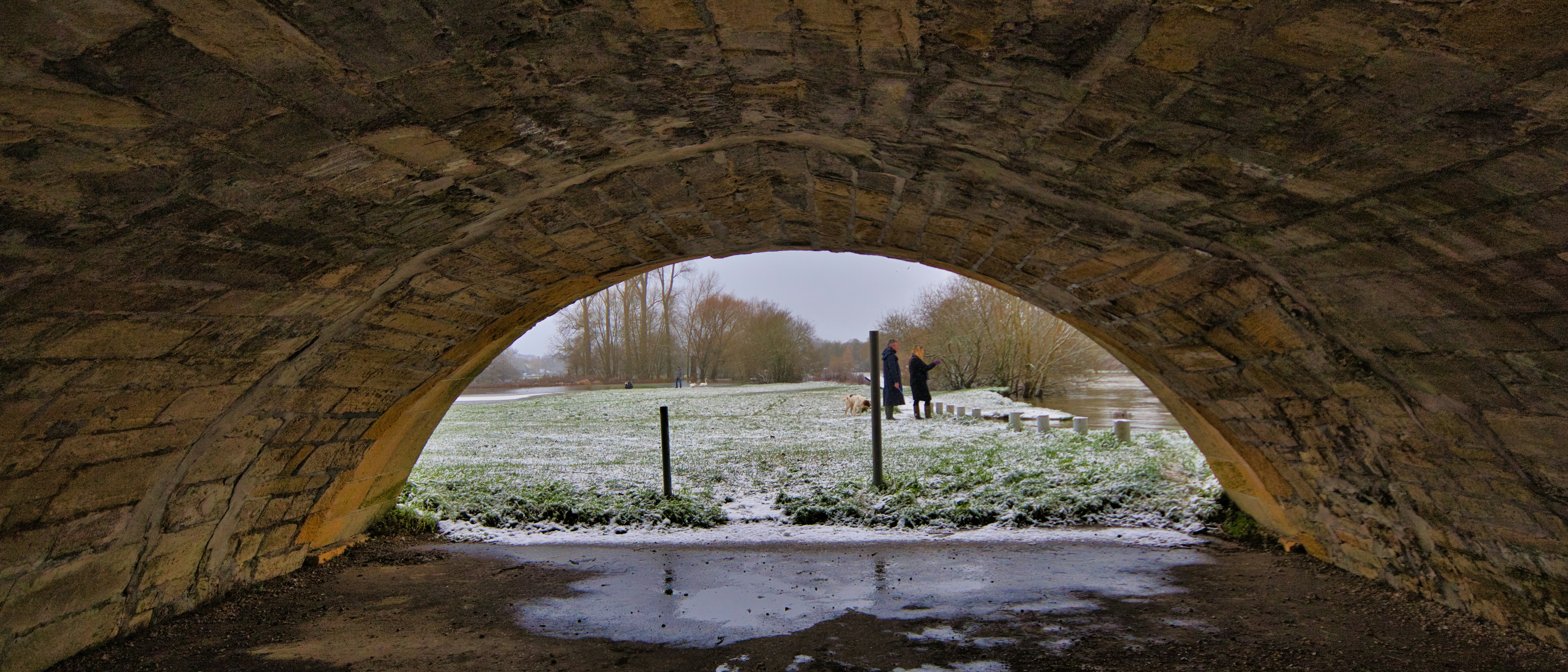 Stone Arch Framing a Frosty Riverside Stroll