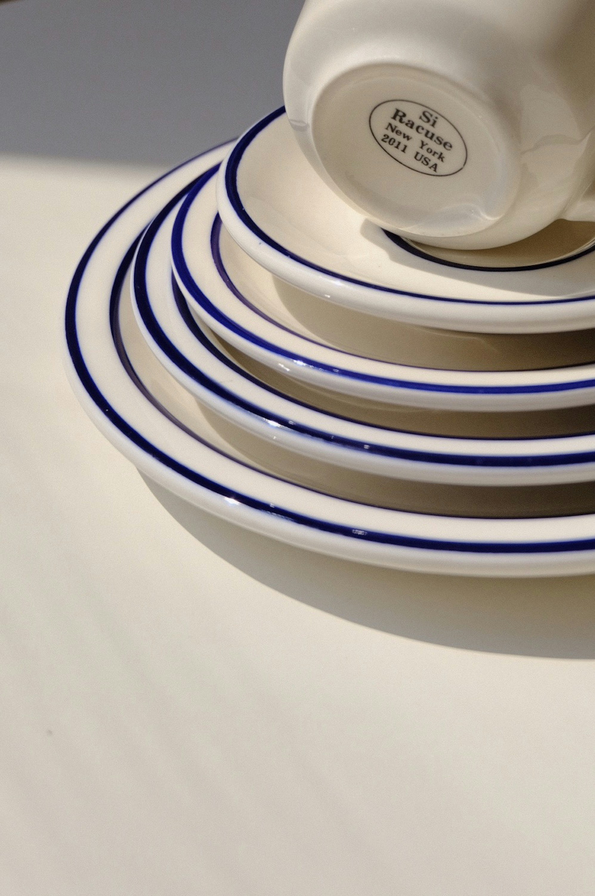 Ceramic Geometry: A Stack of White Plates Framed by a Cup's Circular Seal