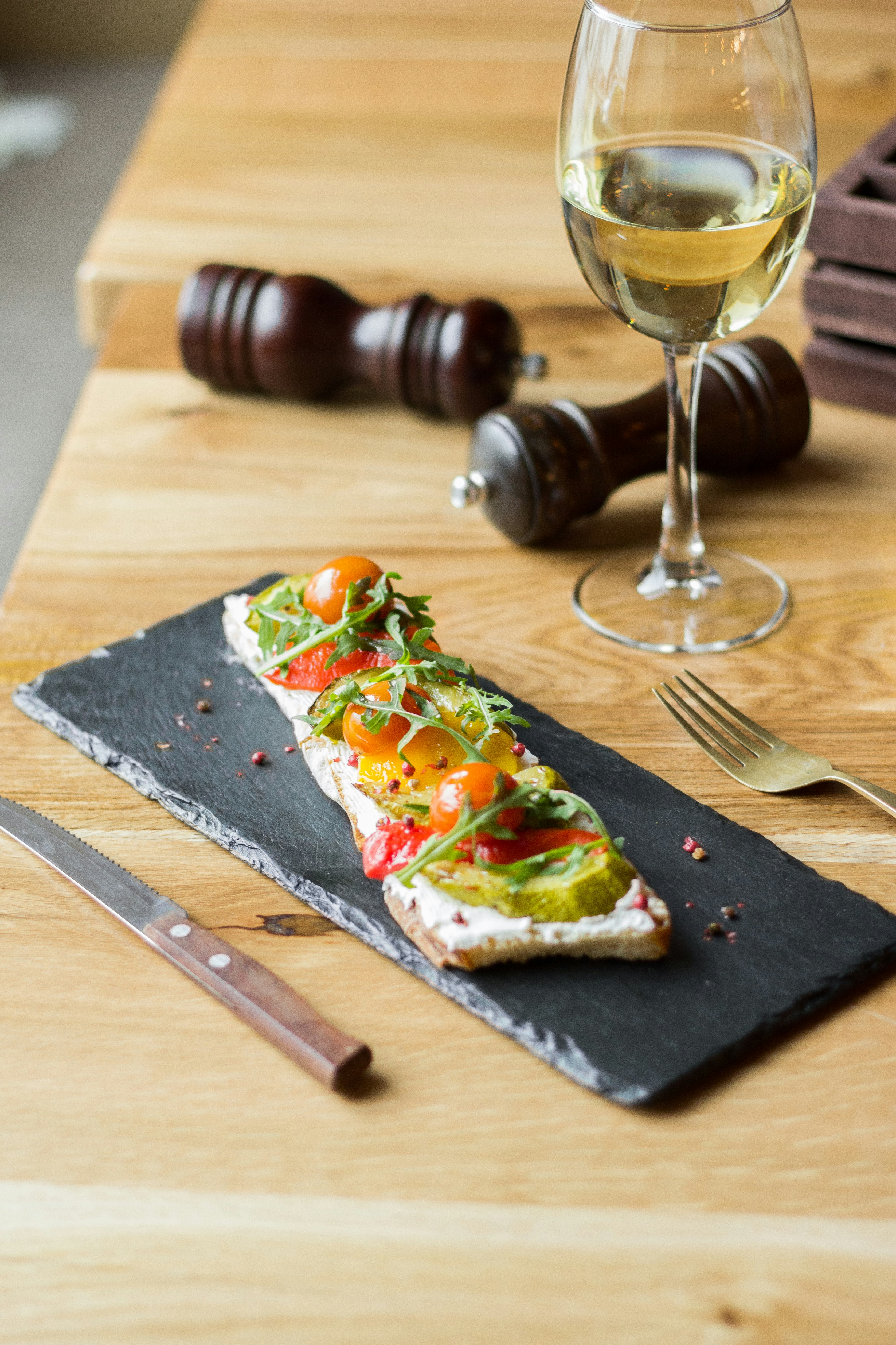 Crisp crostini on slate with wine and pepper mill