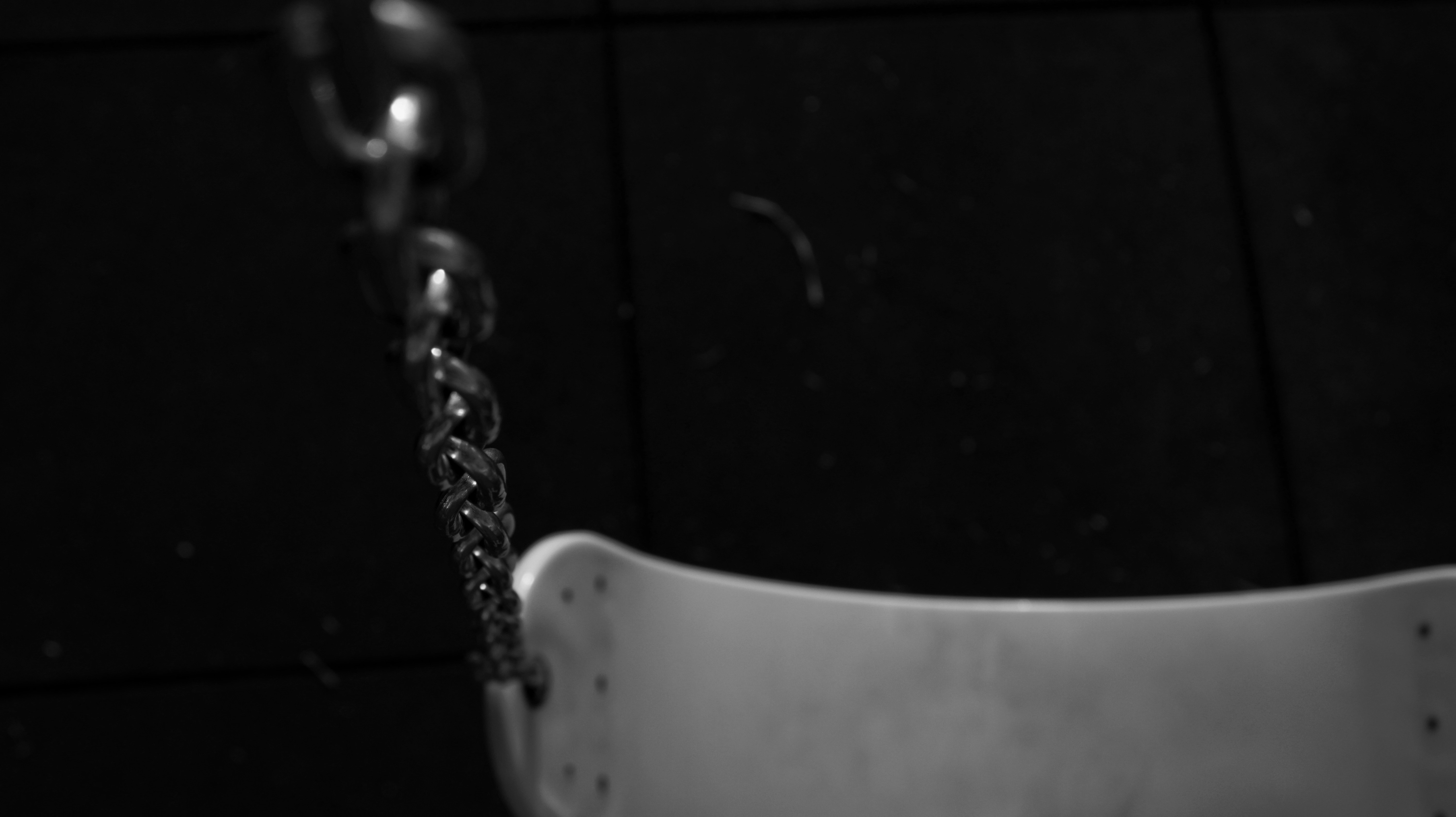 Close-up of a swing's chain and seat in a dimly lit playground, emphasizing the stillness and nostalgia of childhood play. 