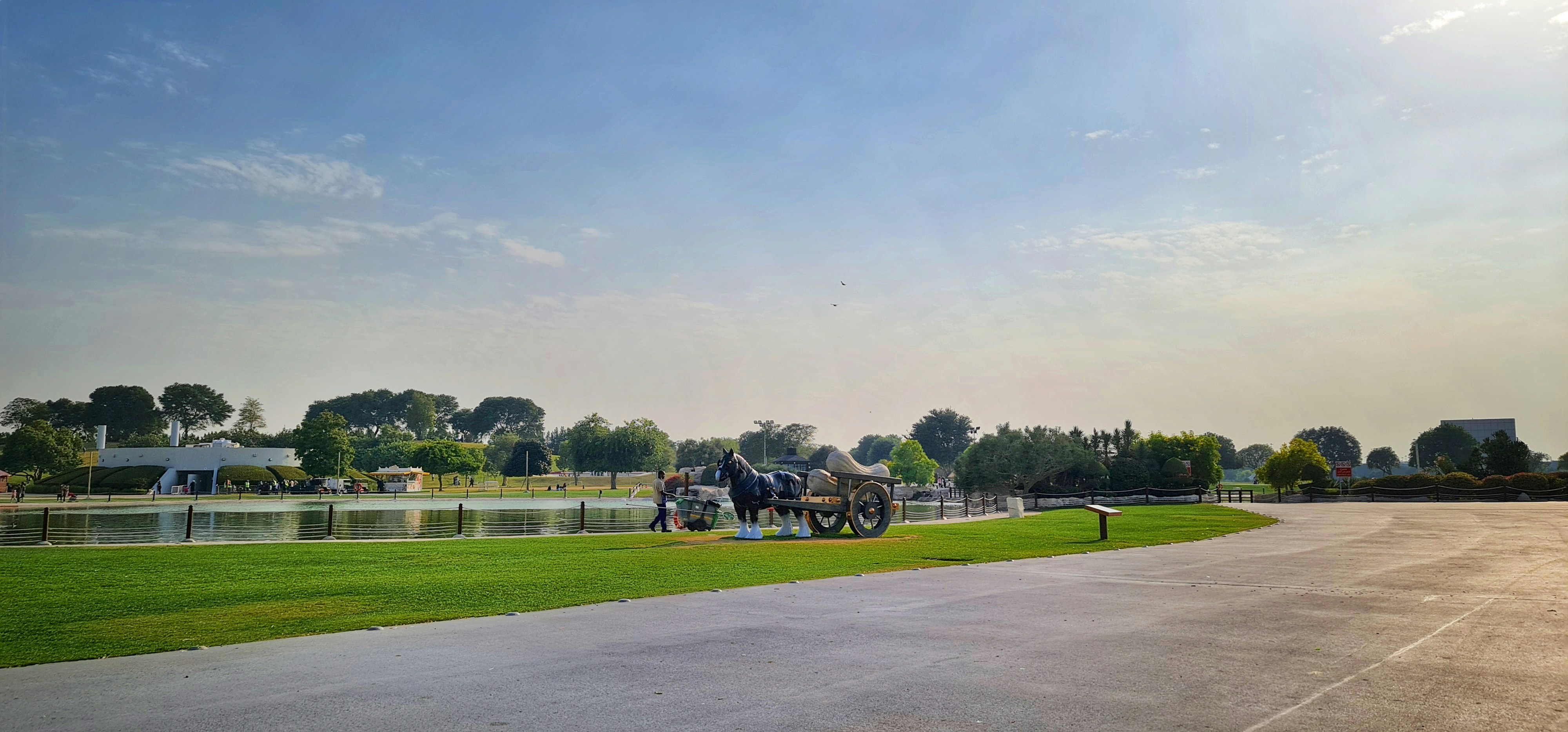 A vintage horse-drawn carriage rests beside a tranquil lake, surrounded by greenery and a serene landscape.
