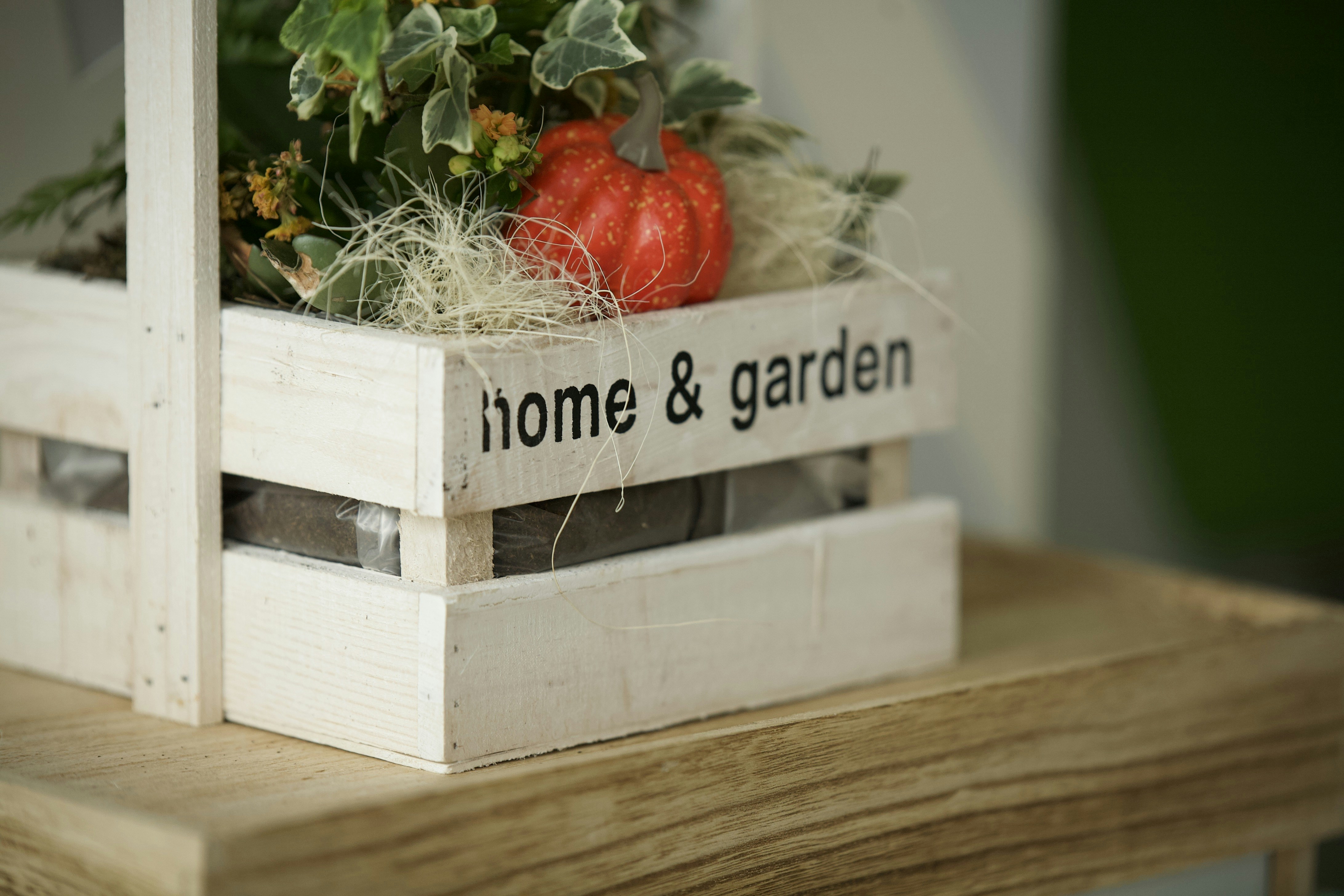 Wooden crate filled with greenery and a decorative pumpkin, labeled 'home & garden.'