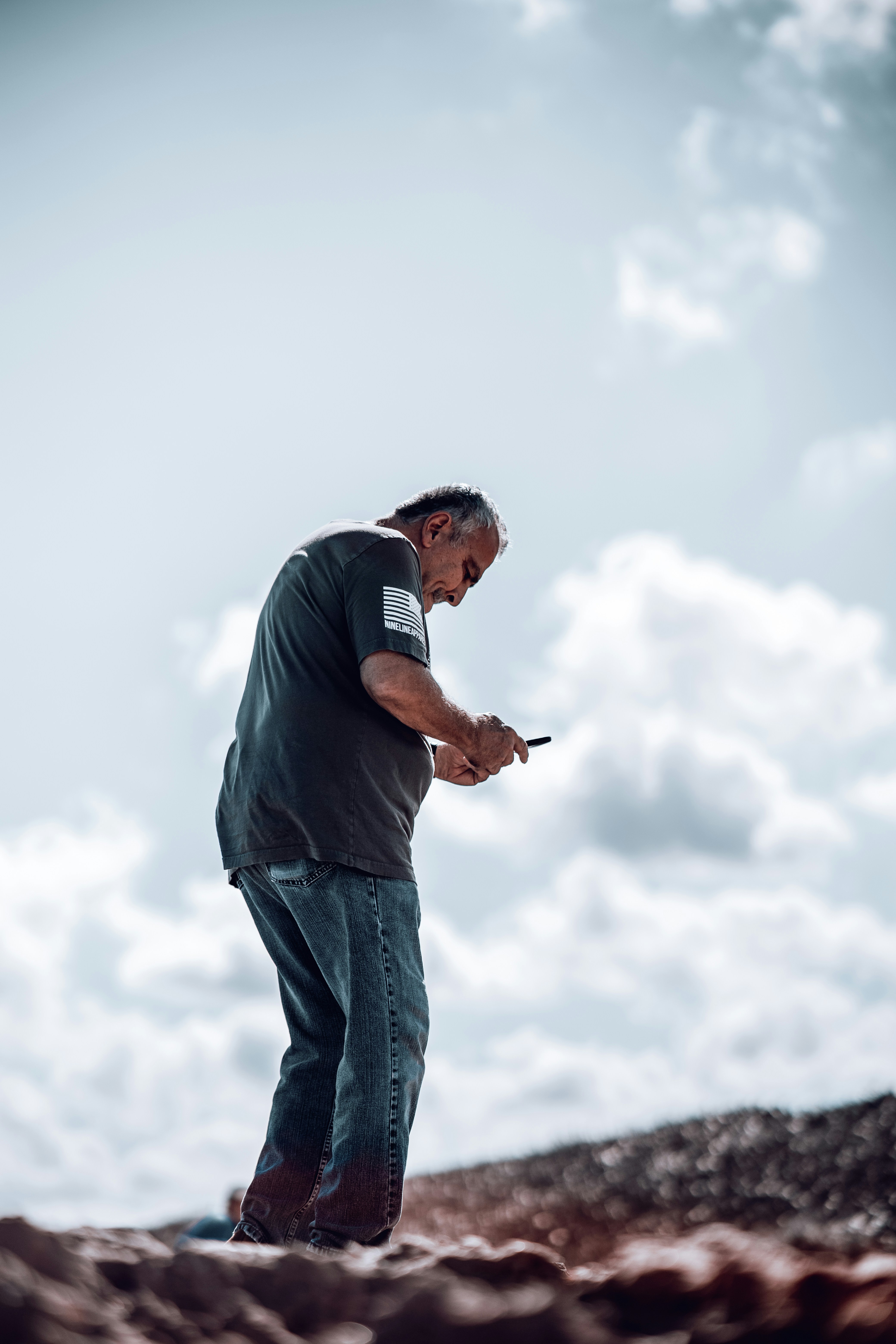 Quiet Moment: A Man Focused on a Phone Under Open Sky