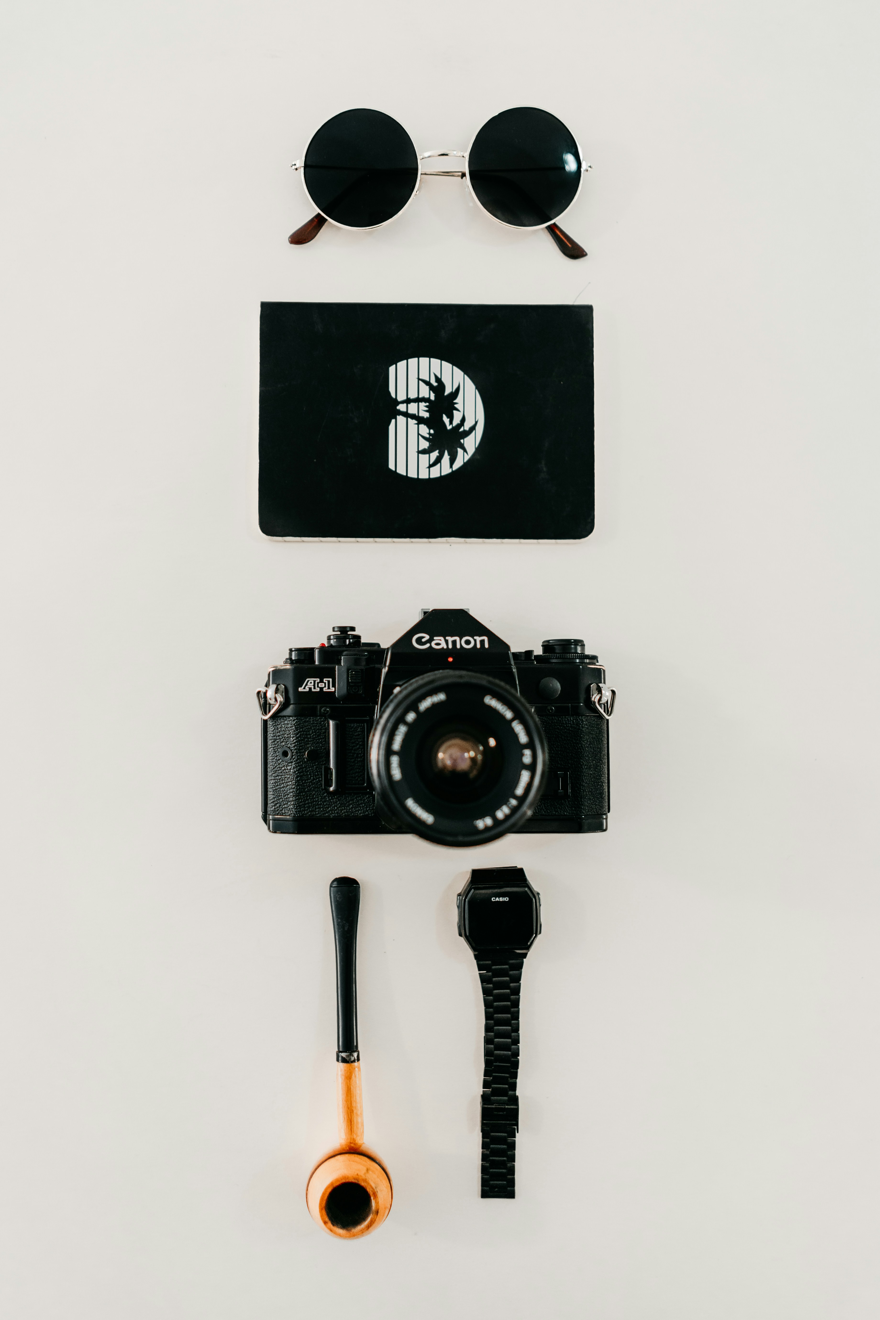 Minimalist Flat-Lay: A Vintage Canon Setup with Palm-Logo Notebook and Sunglasses