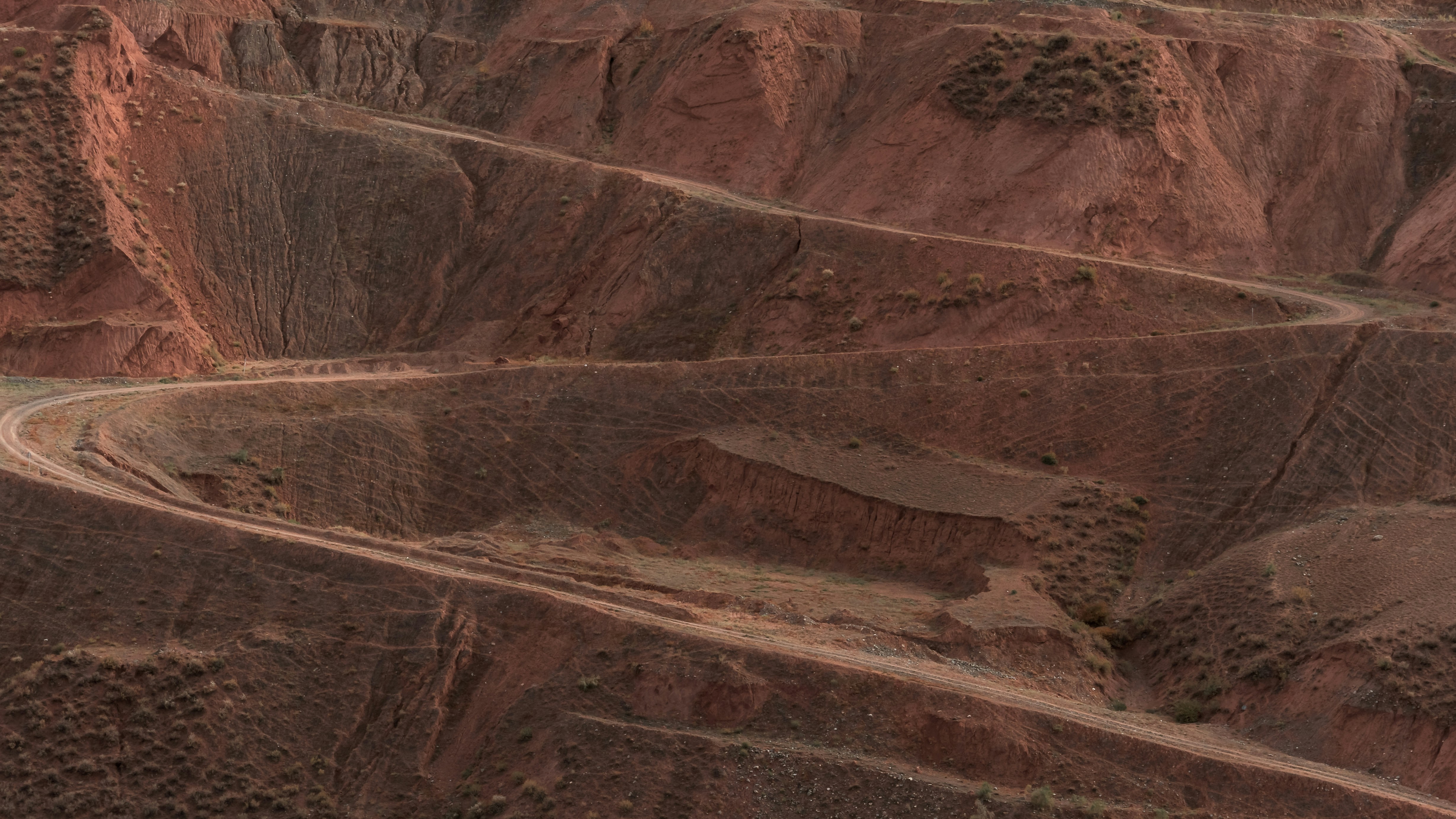 Aerial view of winding trails etched into rugged, brown mountains.