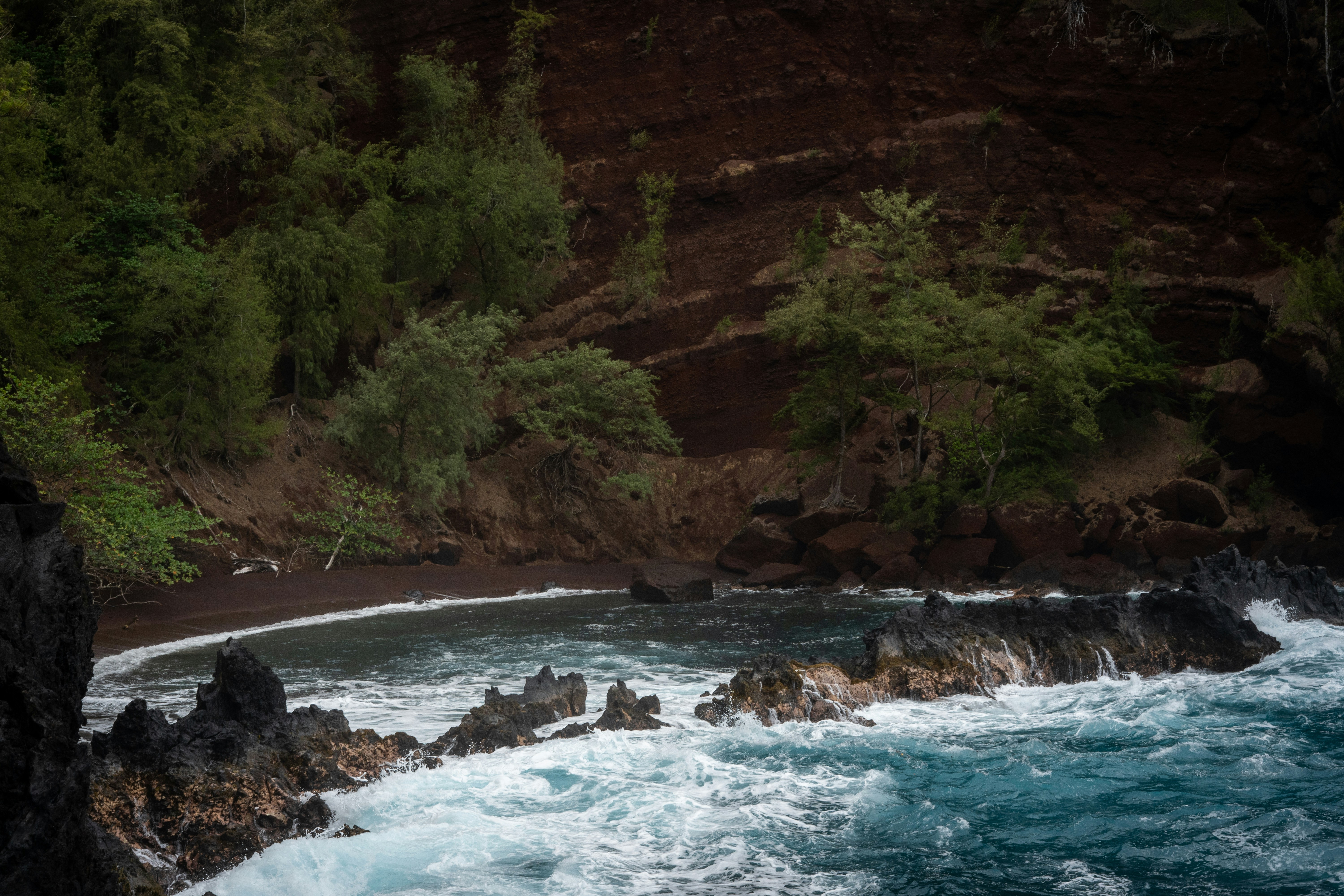 Rugged Cove: Basalt Rocks Meet Turbulent Surf Beneath Green Cliffs