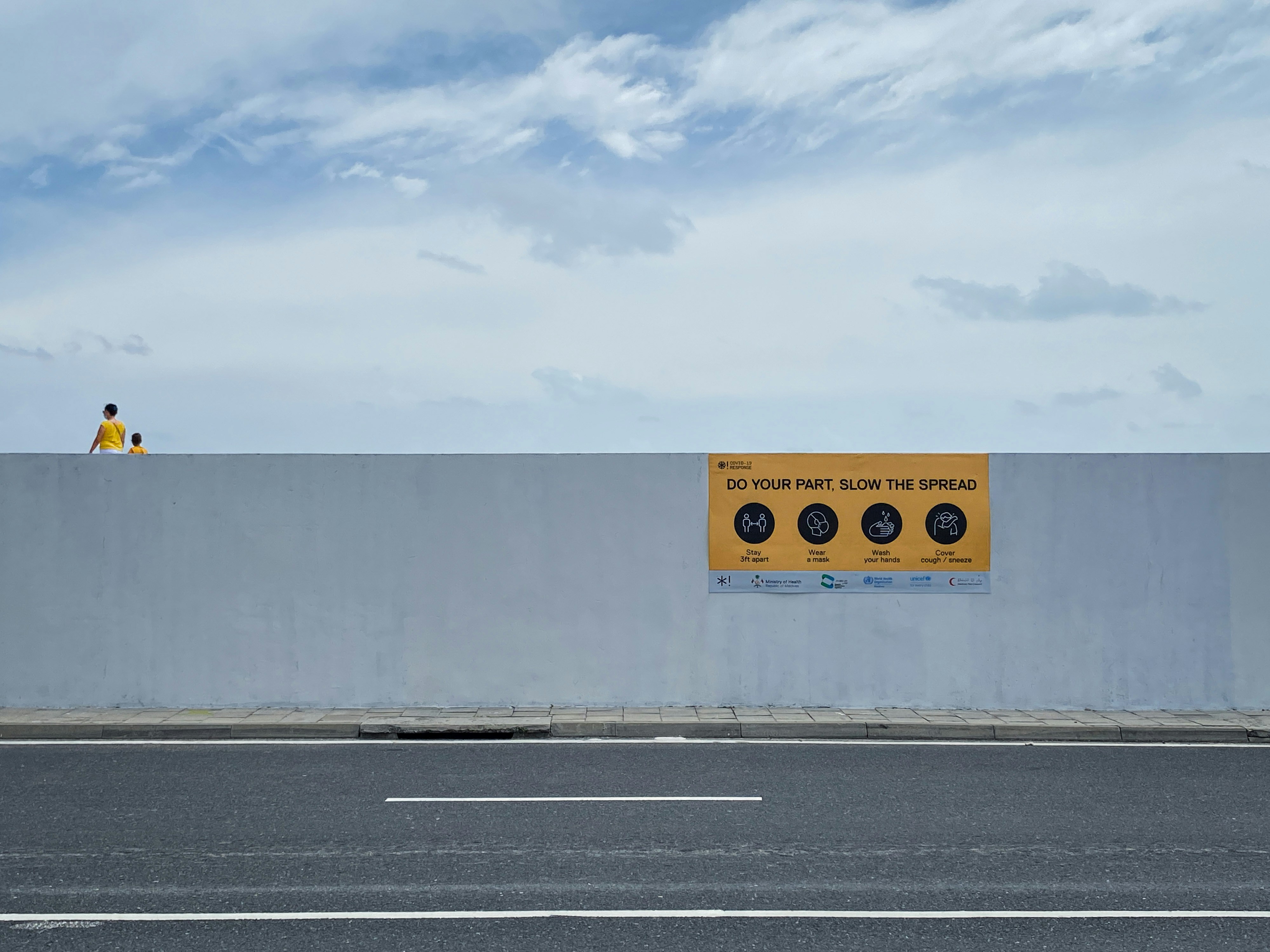 Yellow Safety Sign on a Quiet Highway Barrier Beneath an Expansive Sky