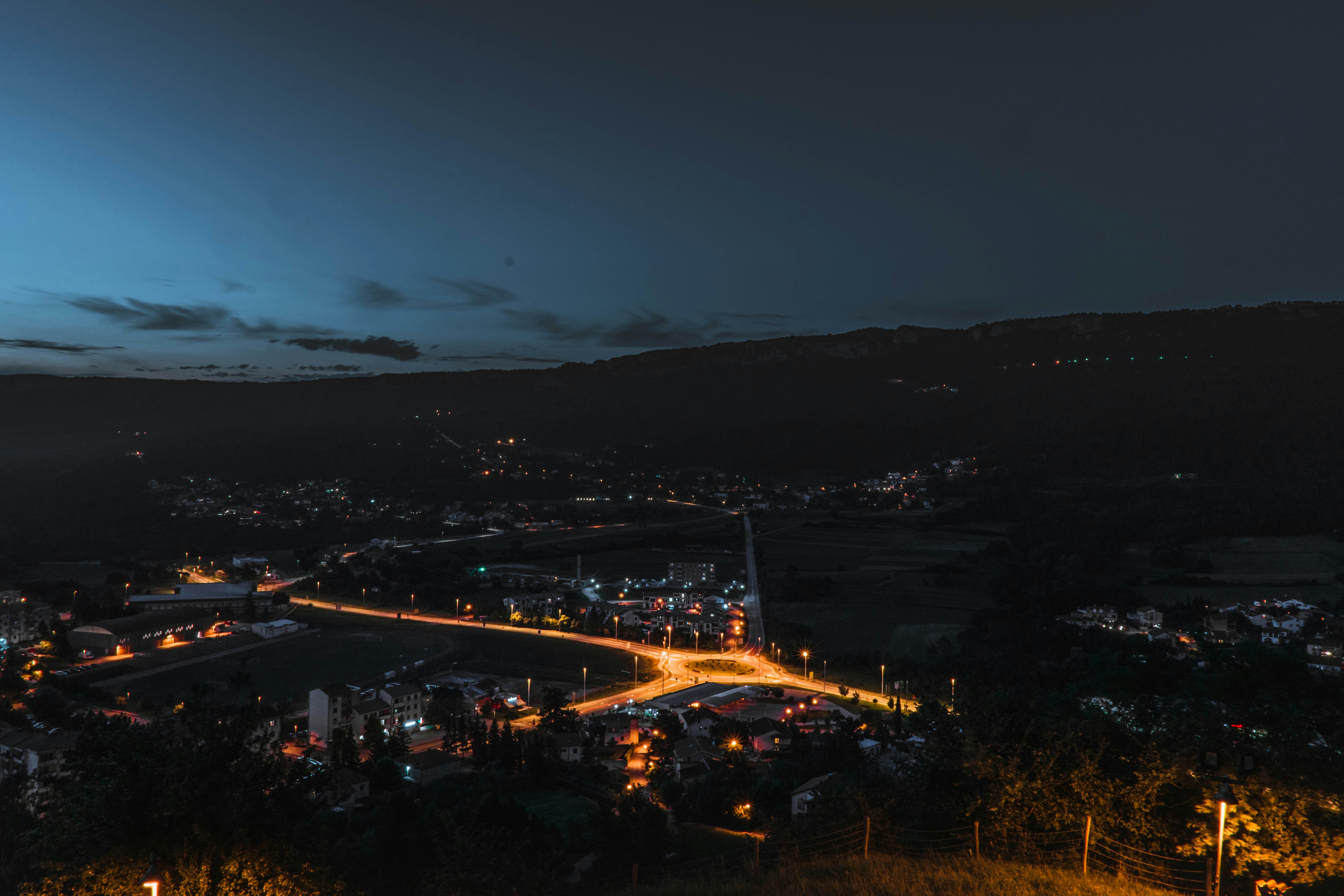 Illuminated cityscape under a twilight sky with streetlights defining the urban landscape.