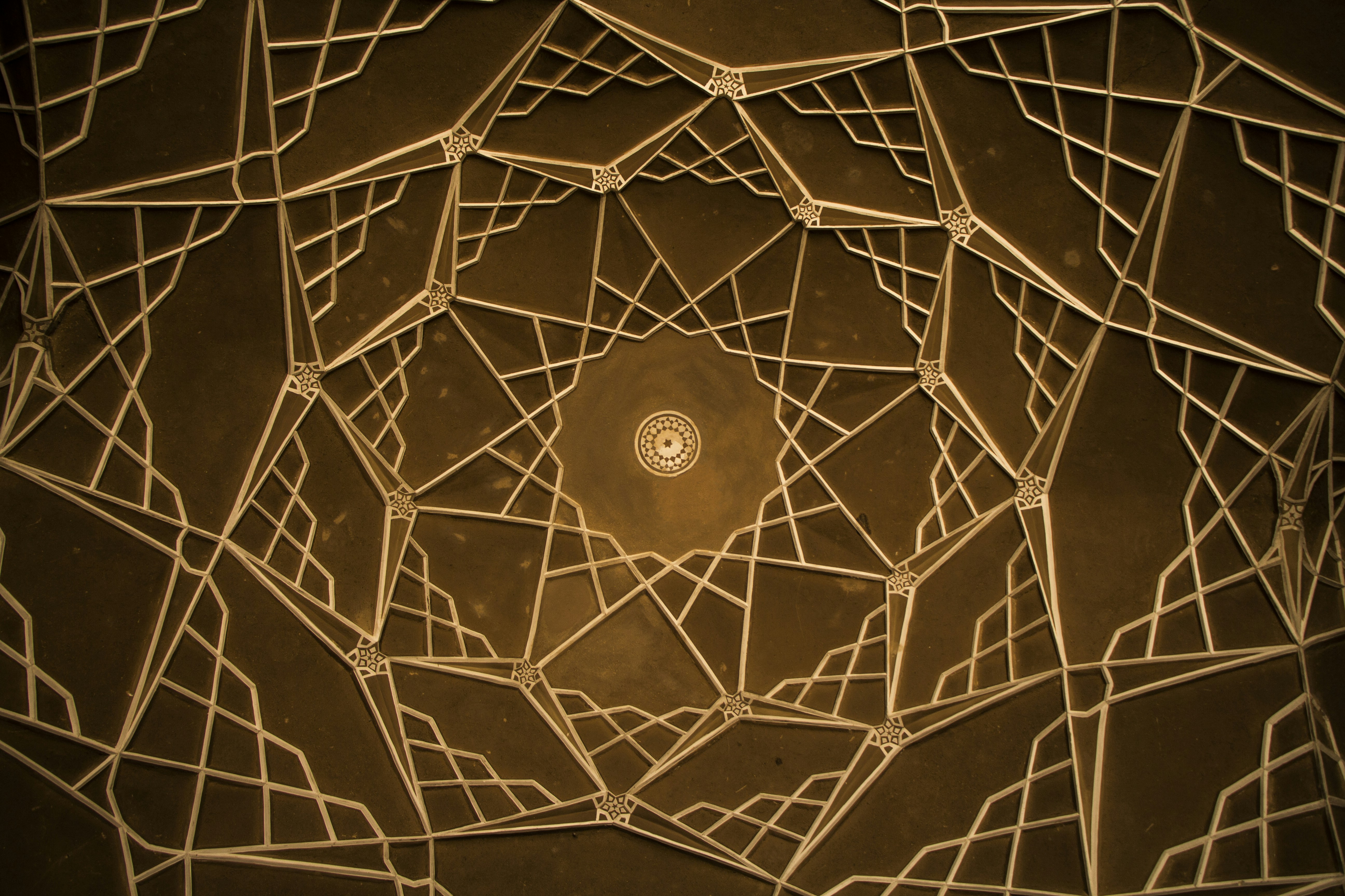 Intricate geometric patterns on a dome ceiling with a warm central light.