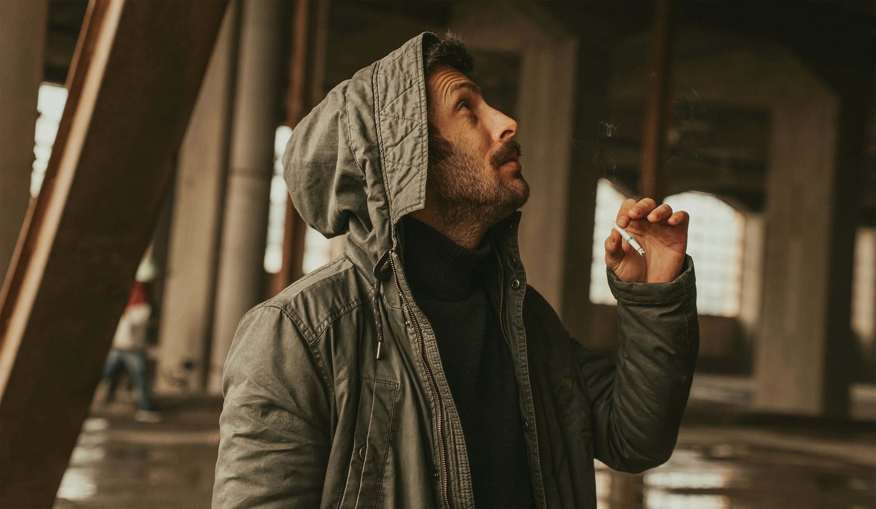 Glimmer Through Steel: Hooded Portrait in a Dim Warehouse
