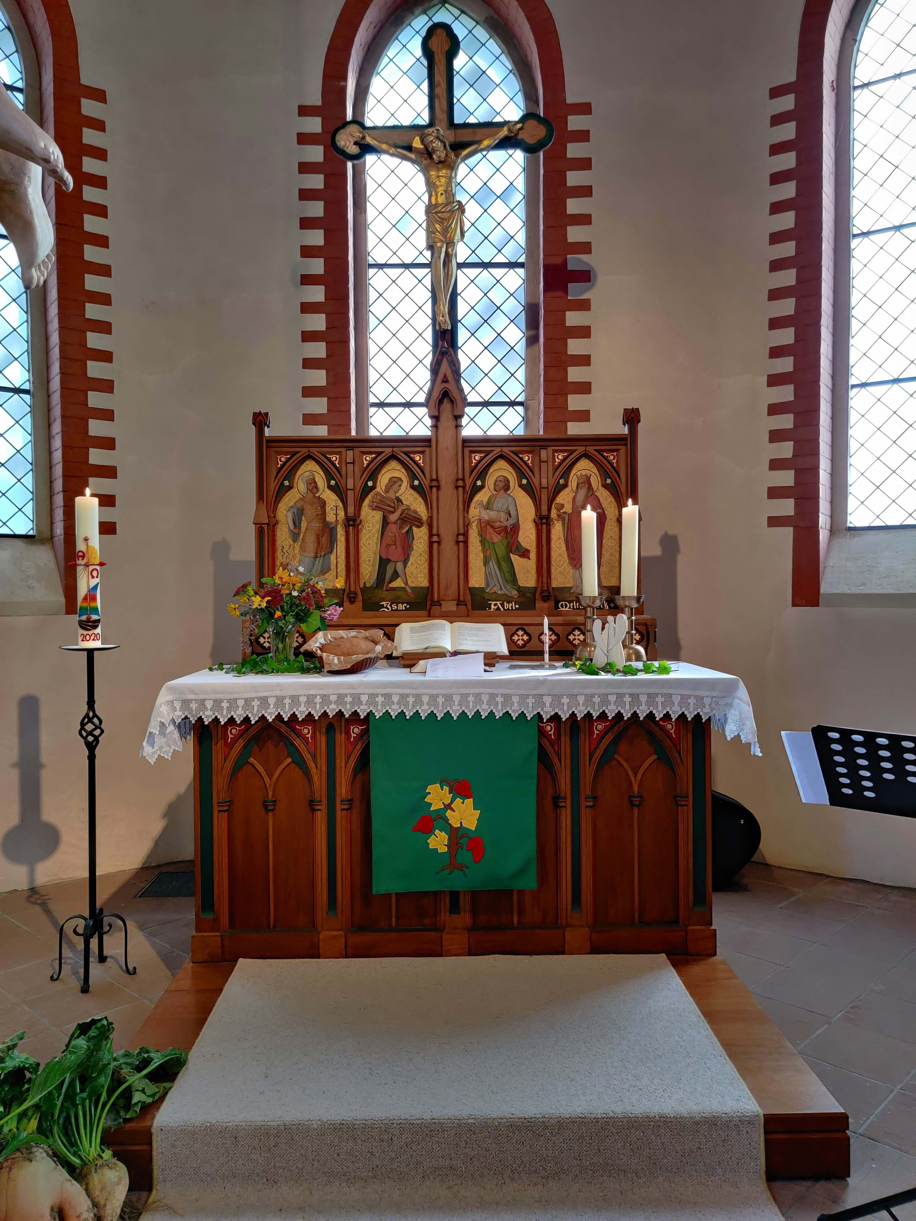 Intricate wooden altar adorned with candles and floral arrangements in a serene church interior, highlighting spiritual elements. 