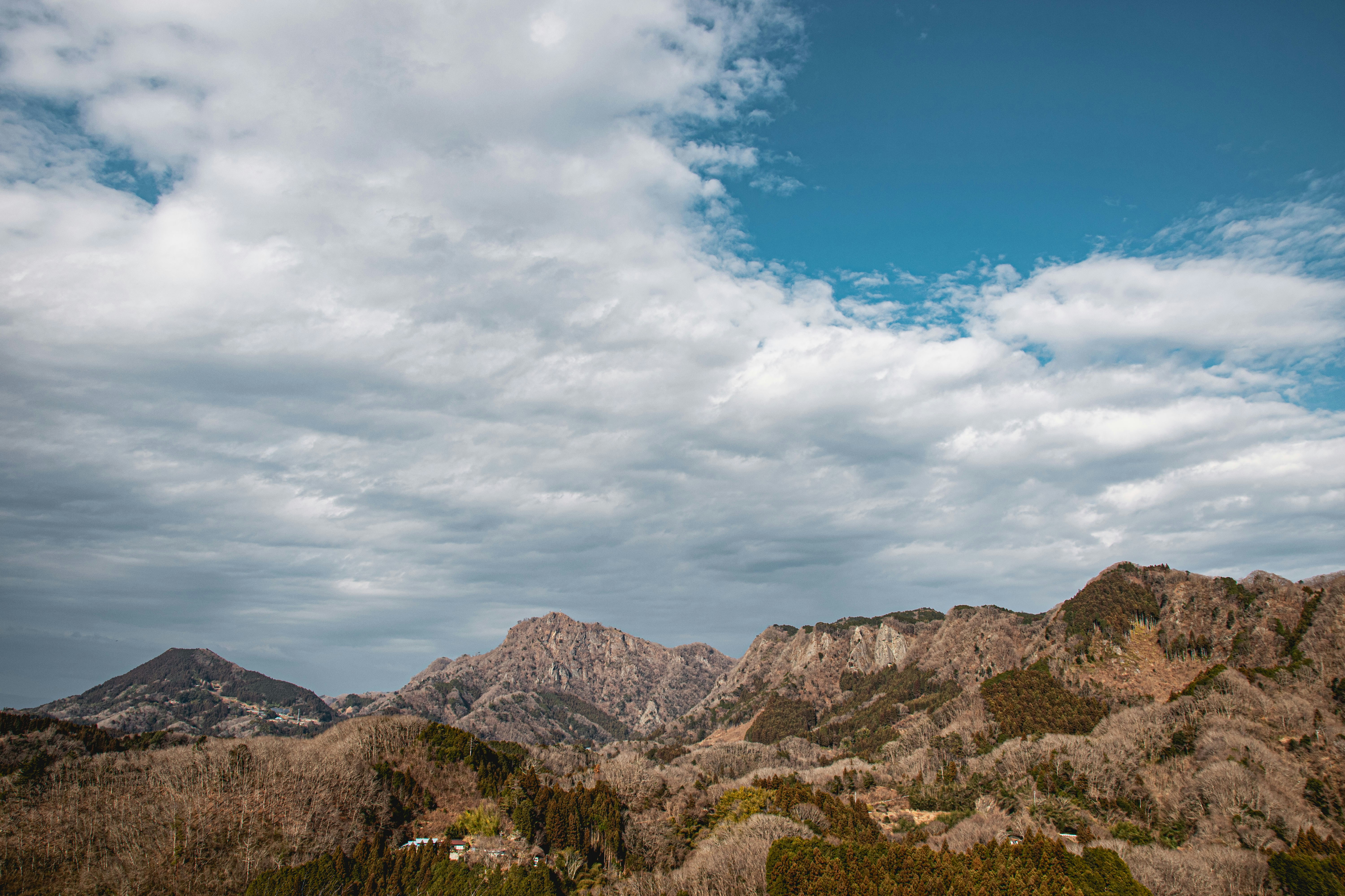 Mountain landscape with rocky peaks beneath a dramatic cloud-filled sky.
