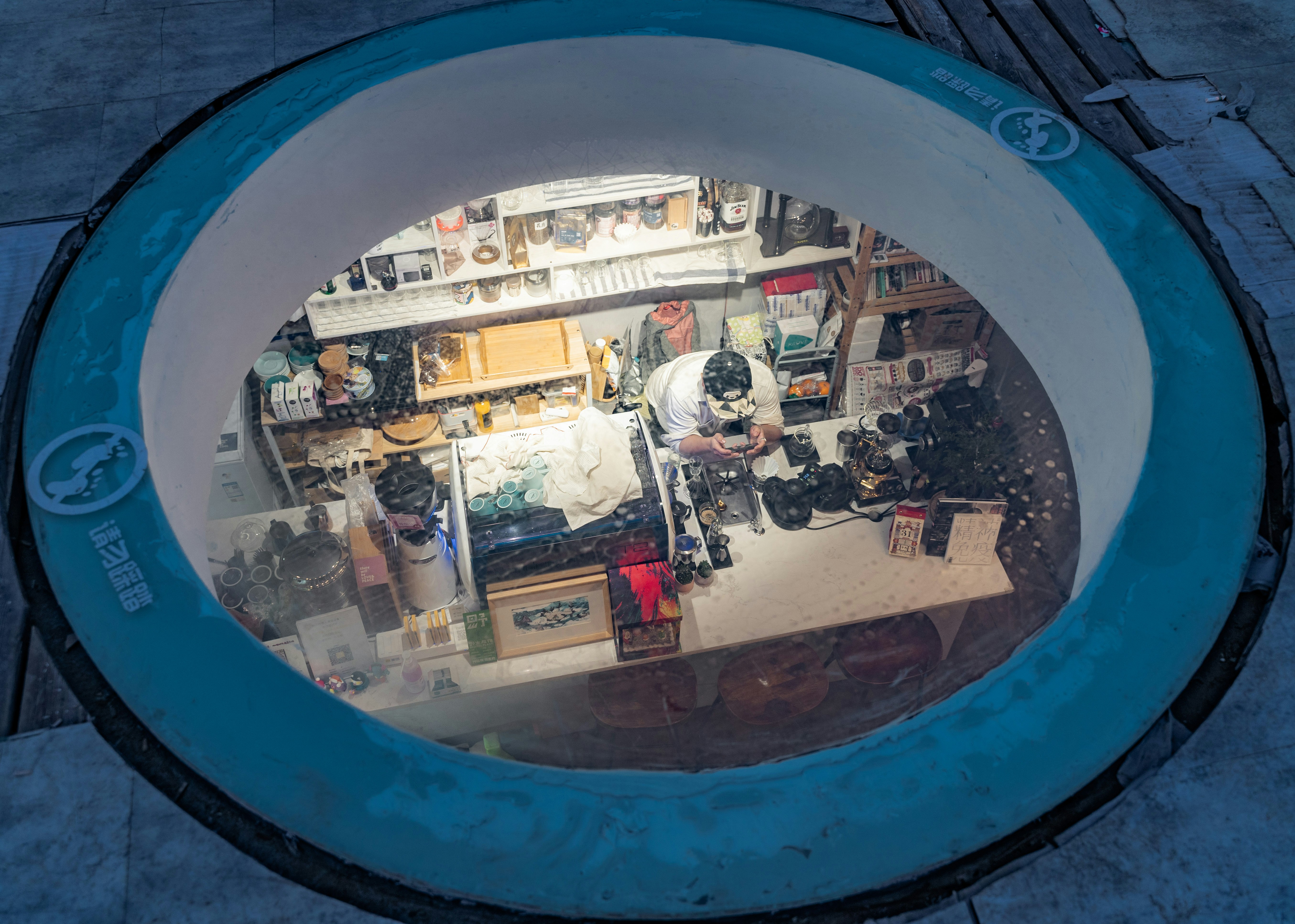 Circular Portal into a Busy Shop: A Top-Down Peek Through a Manhole
