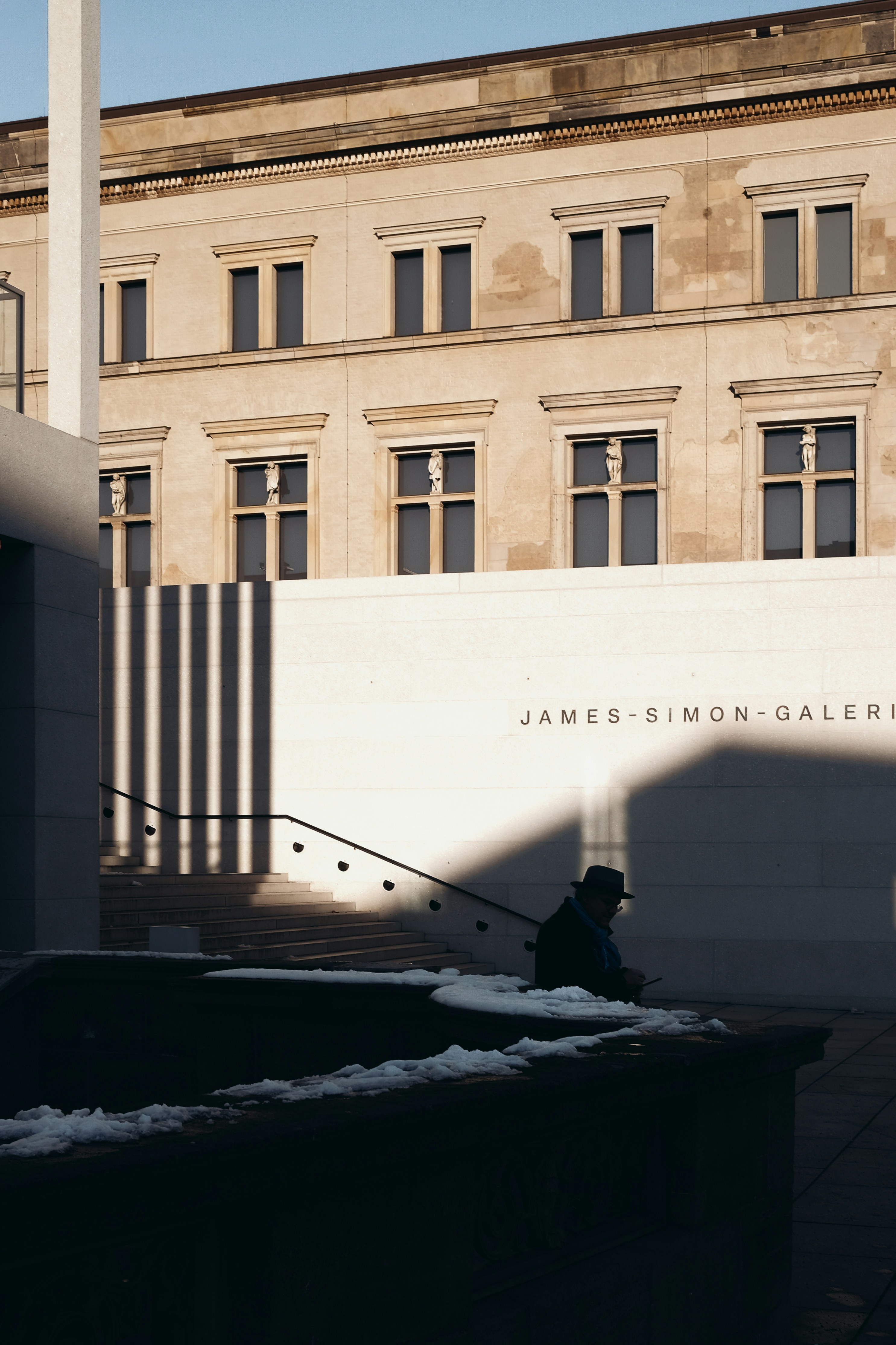 Lone Figure in Shadow Over James-Simon-Galerie Facade