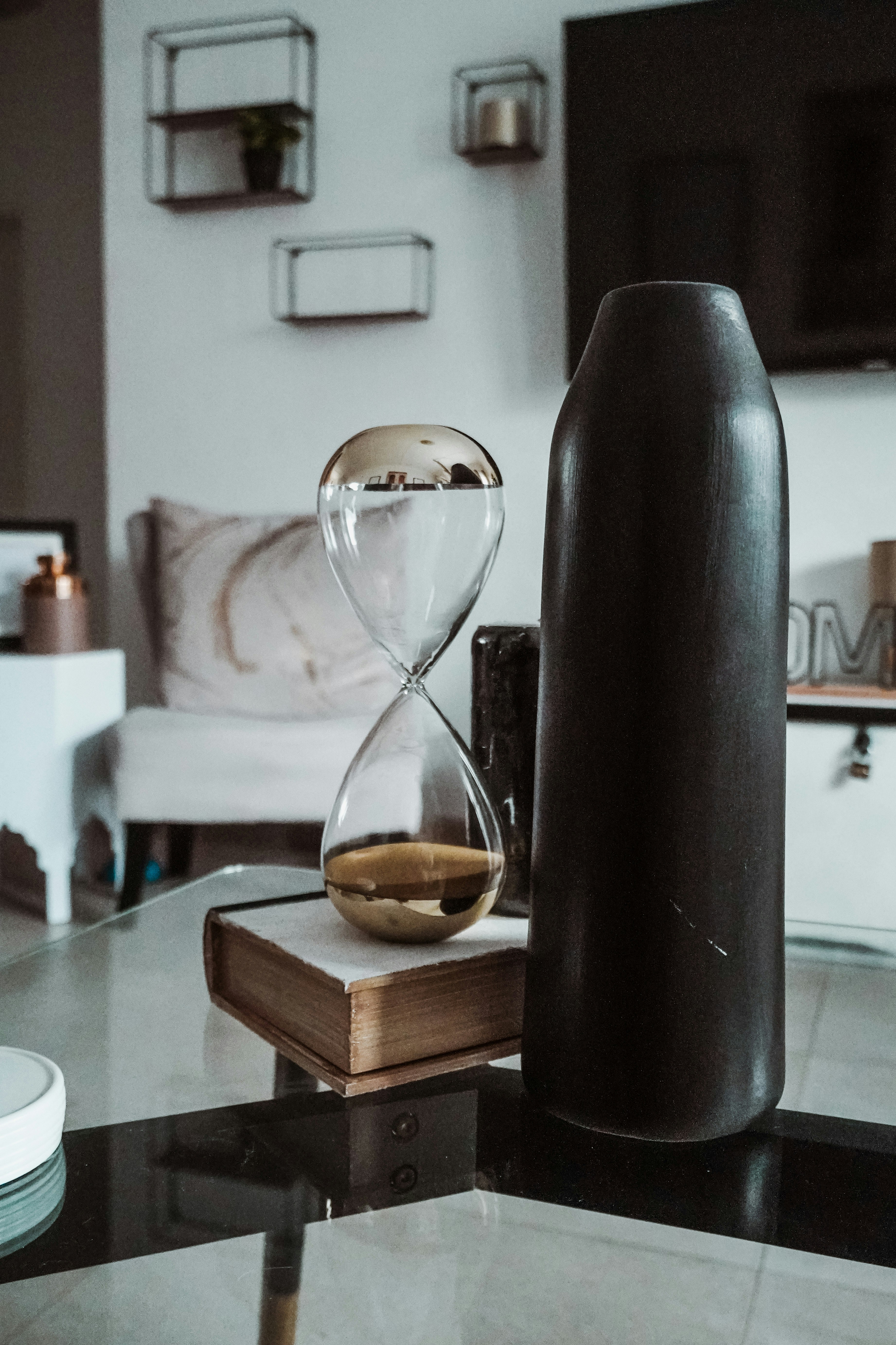 Timekeeper in a Quiet Living Room: Hourglass and a Dark Cylinder