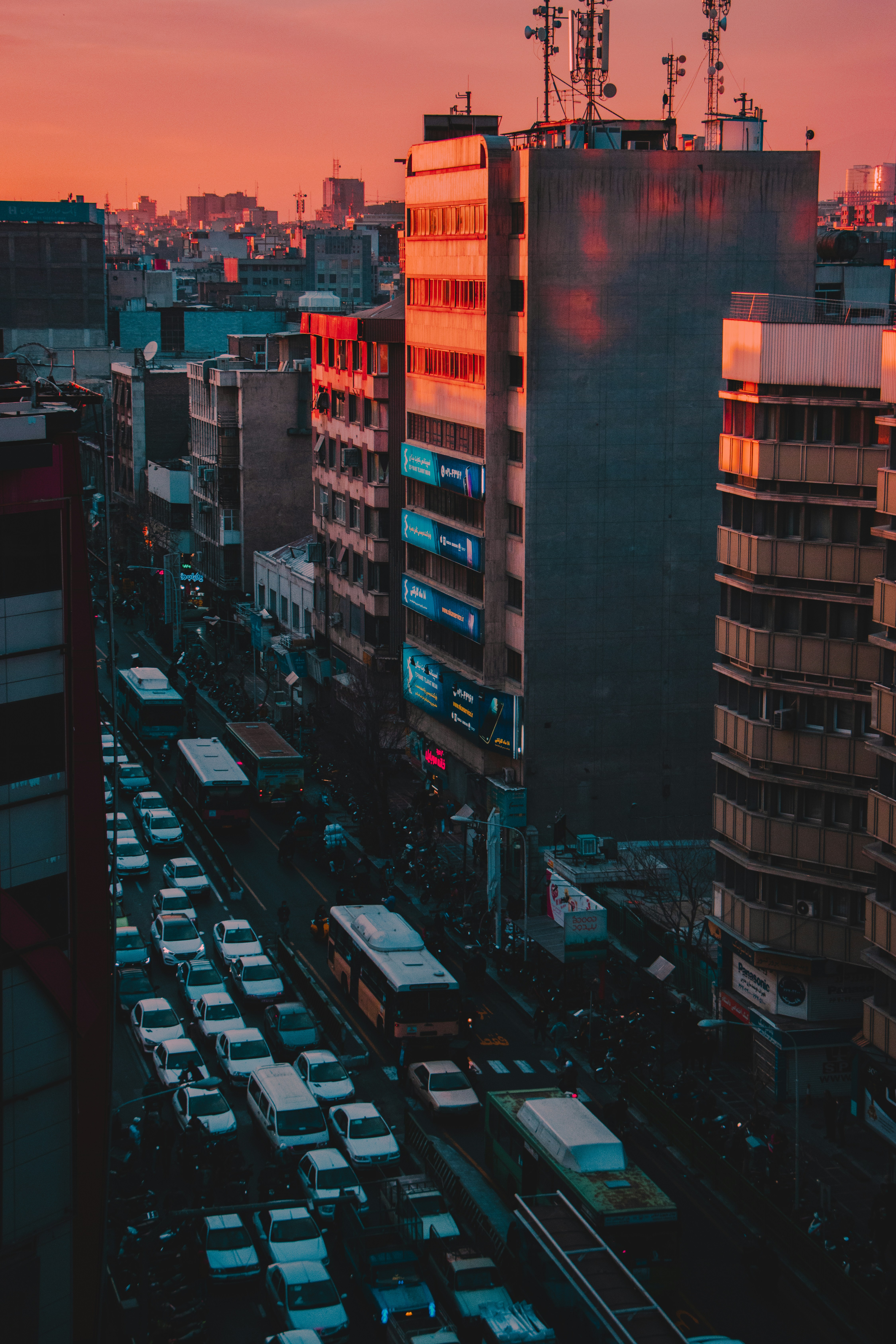 Cityscape at twilight showcasing a busy street filled with vehicles, illuminated buildings, and a vibrant sky. The image captures the essence of urban life as day transitions to night.