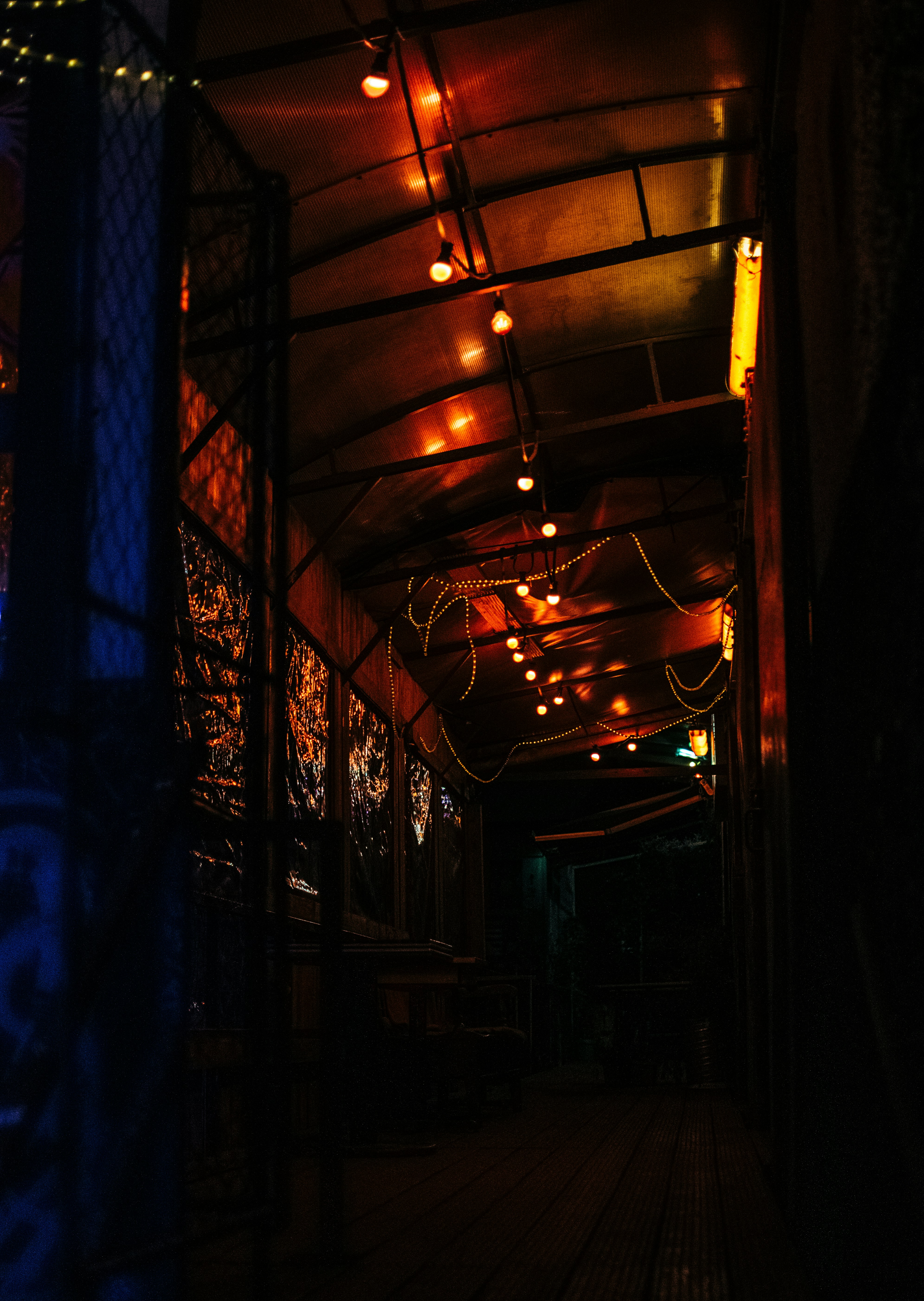 Dimly lit corridor adorned with glowing string lights and vibrant murals, creating a cozy atmosphere at night.