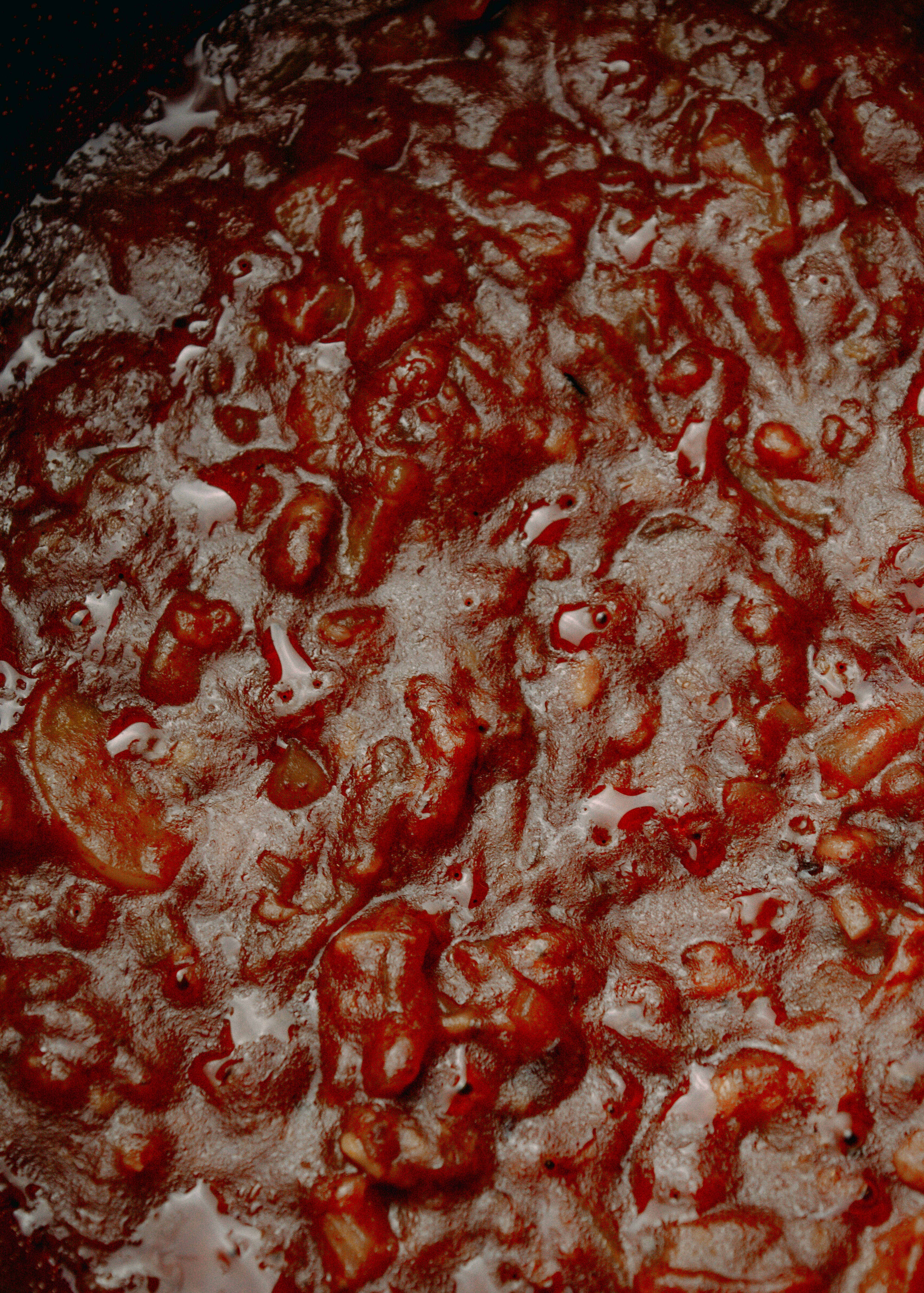 Crimson Foam: Close-Up of Tomato Fragments in Bubbling Sauce