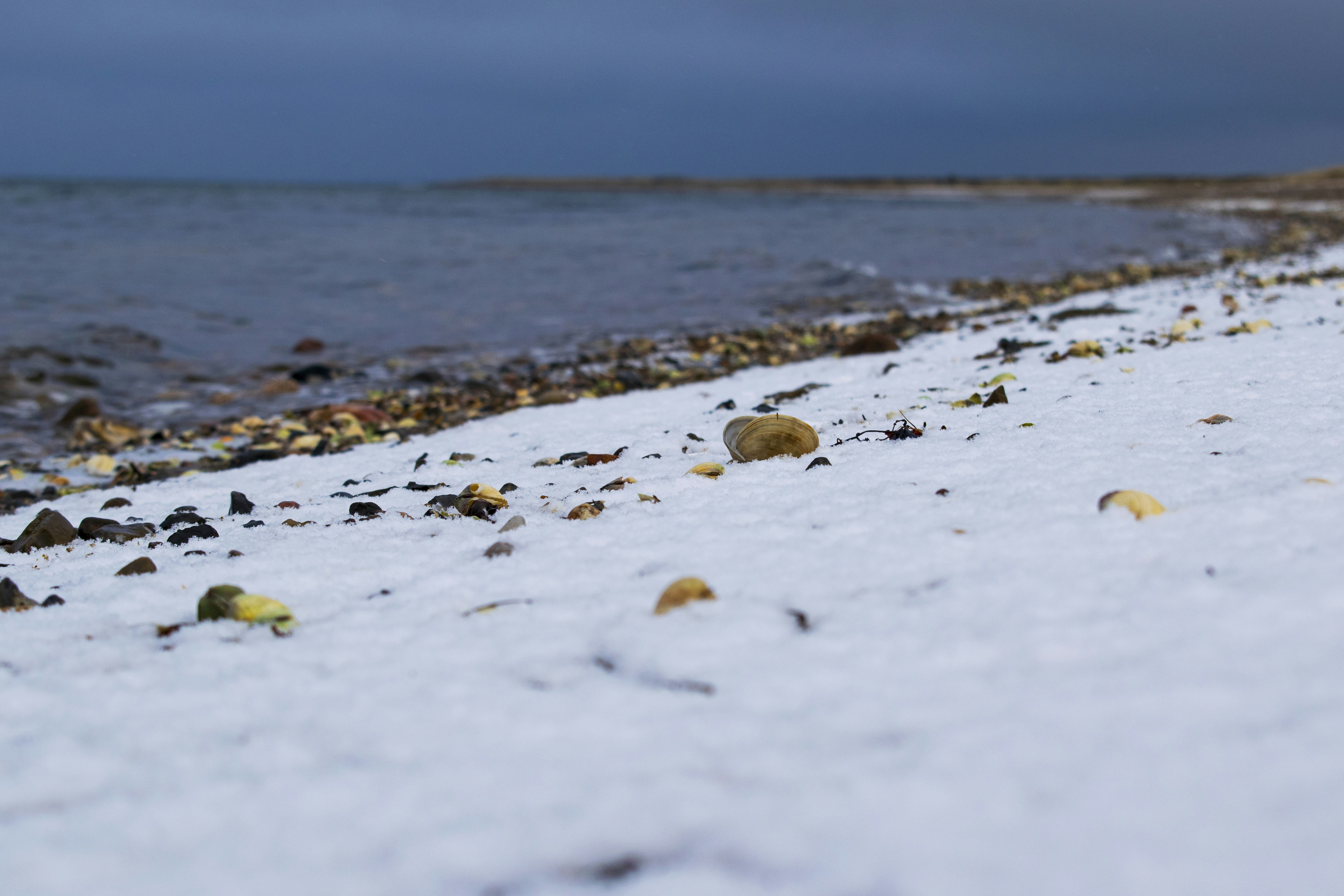 Pebble Chorus Along a Snow-Dusted Shore Under a Slate-Blue Sky