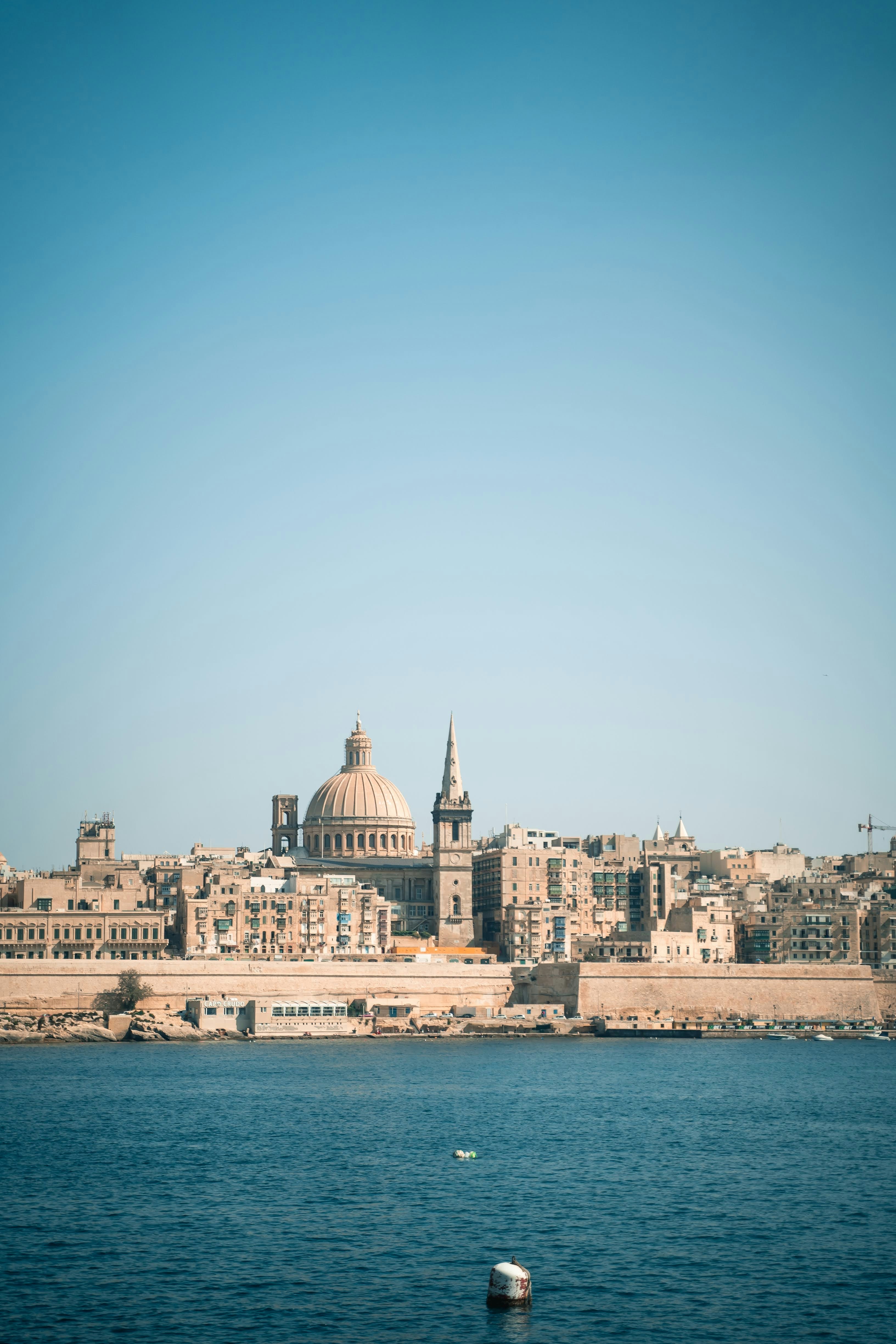 Historic skyline of Valletta, Malta, showcasing its iconic dome and spires against a clear blue sky.