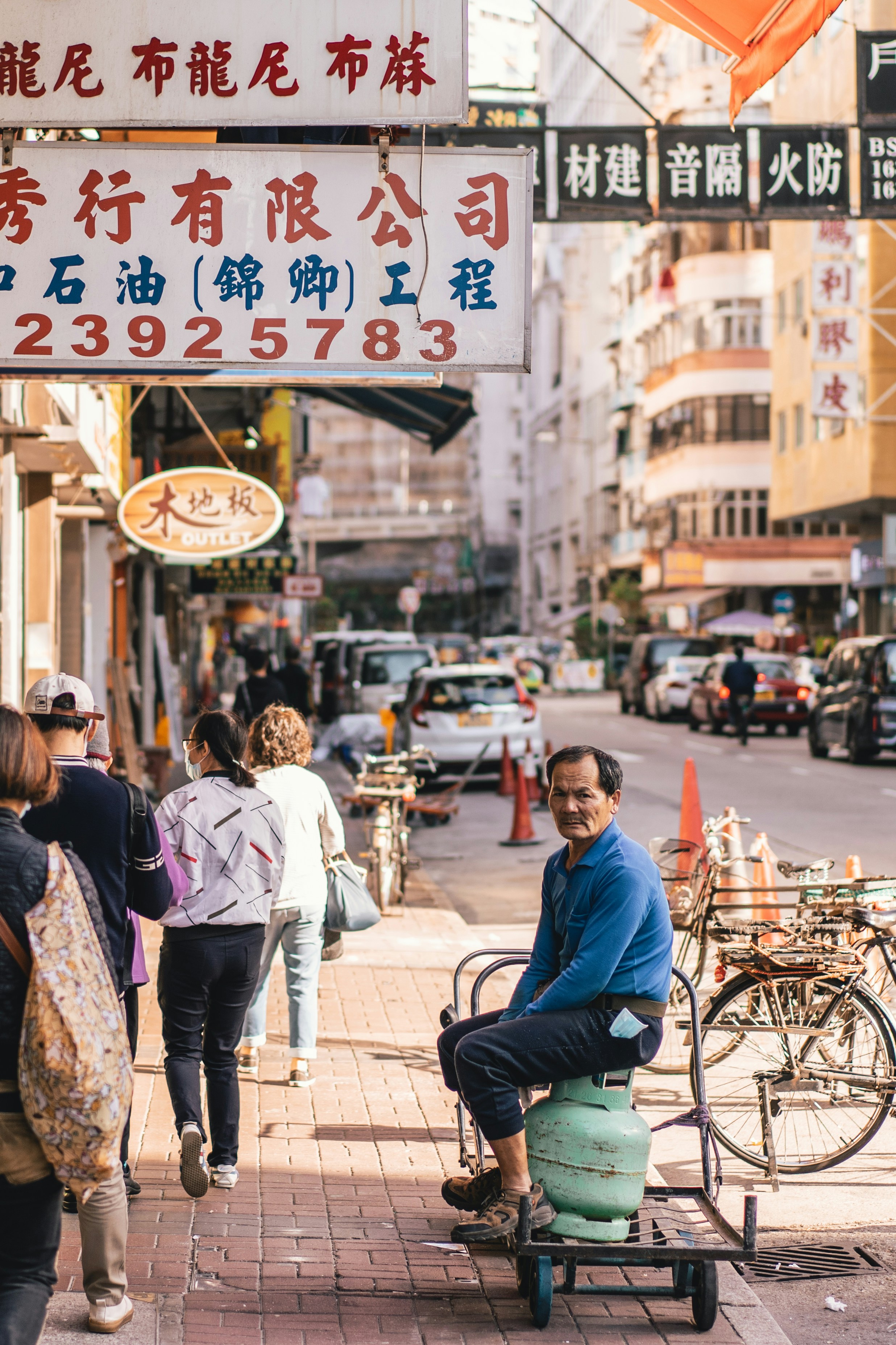 Blue-Shirt Vendor on a Gas-Tank Cart Beneath a Canopy of Storefront Signs