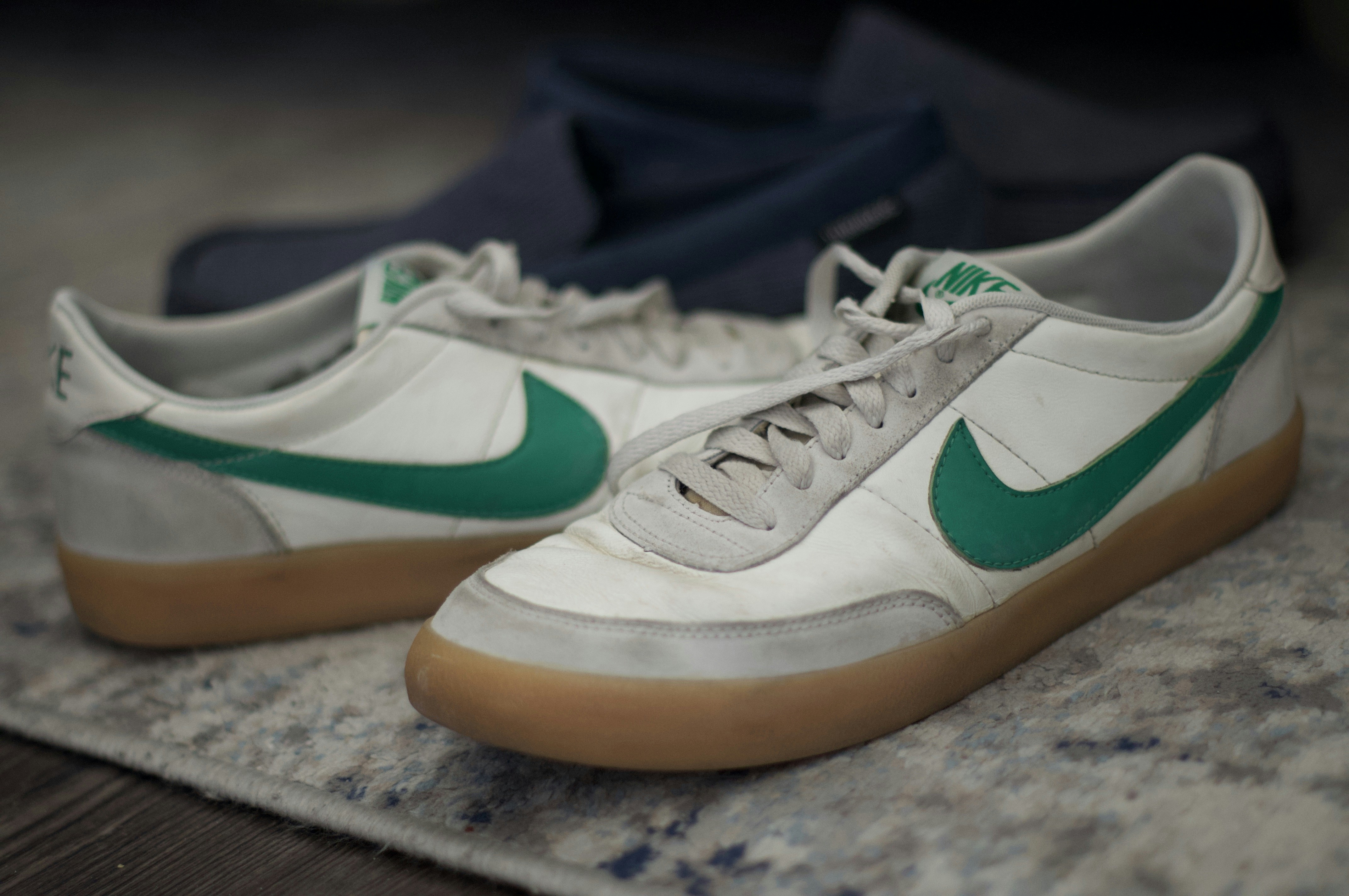 Gum-Soled Nike Sneakers: Green Swoosh Resting on a Textured Rug