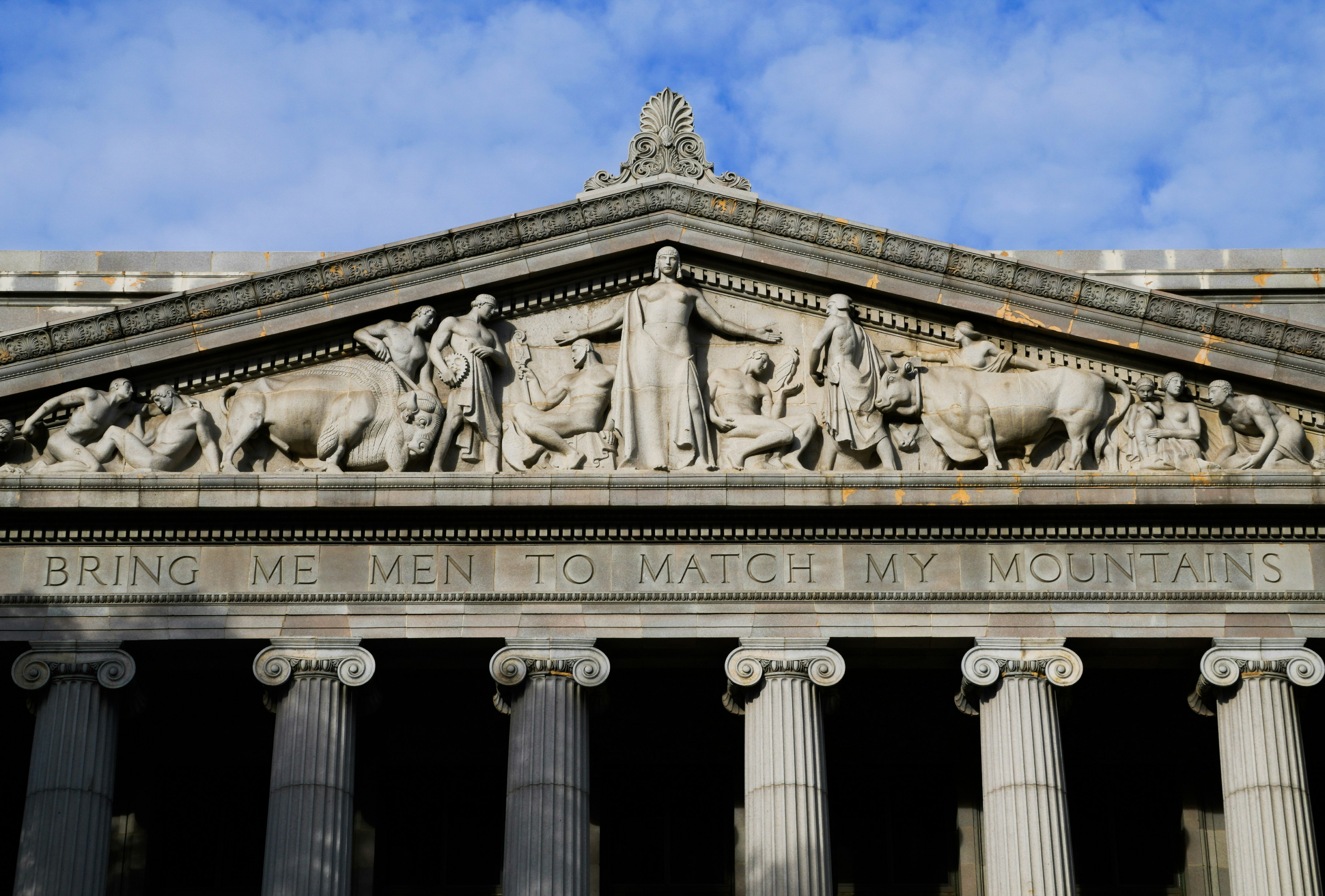 Neoclassical building façade adorned with intricate sculptures beneath a clear blue sky.