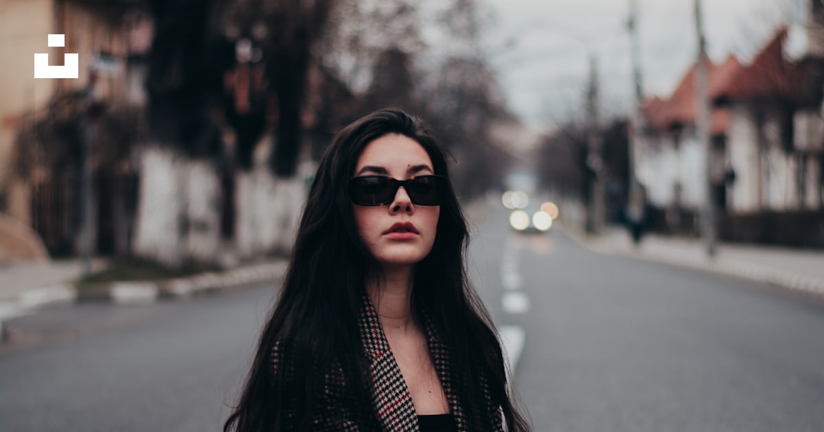 黒と白のチェック柄のドレスシャツと黒いサングラスを着た女性が昼間、道路に座っていますの写真 Unsplashの灰色の無料画像