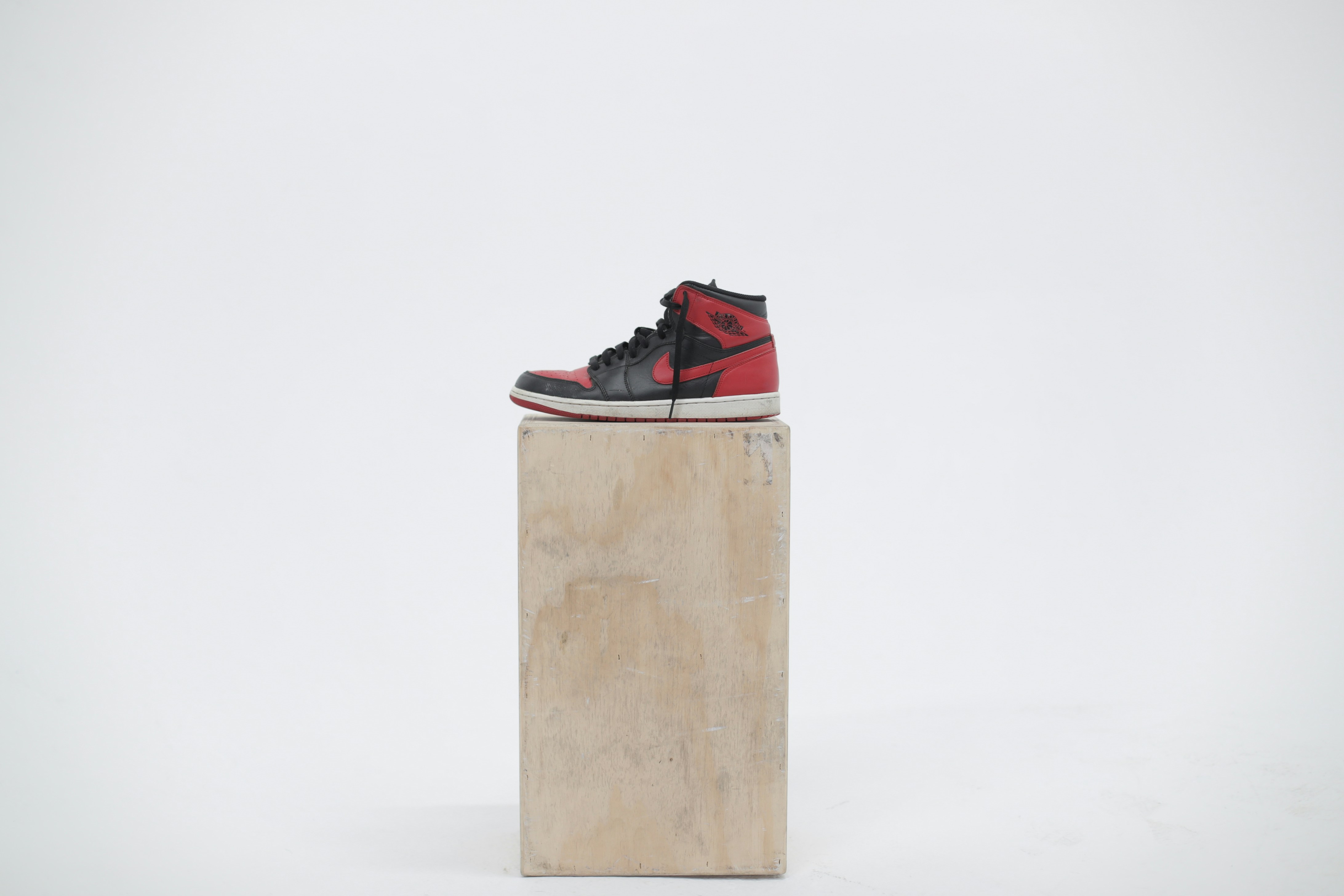 Pedestal Command: A Red-Black High-Top Reigns in a White Studio