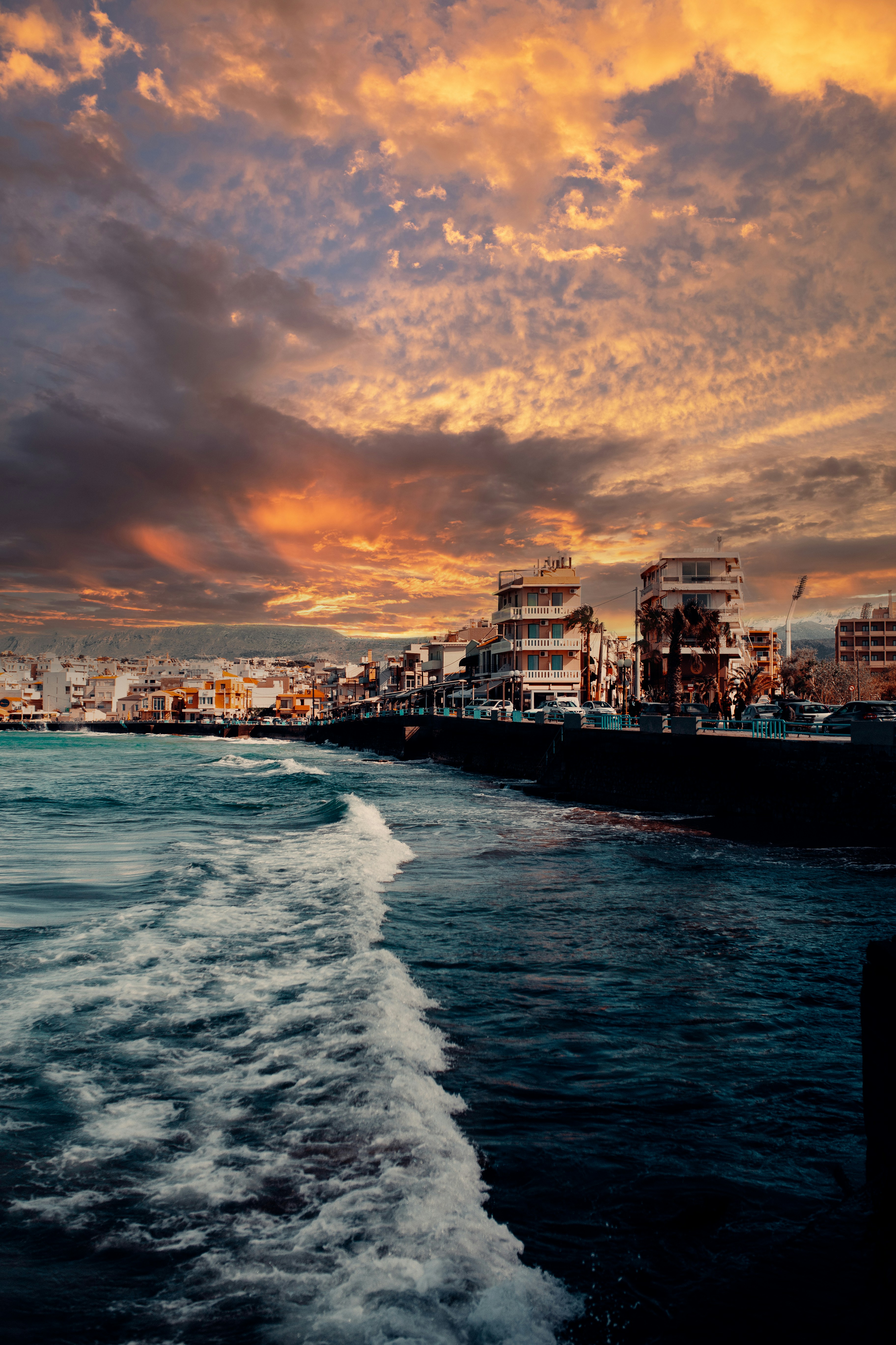 Dusk Harbor Wake: Sunset Over a Waterfront Cityscape