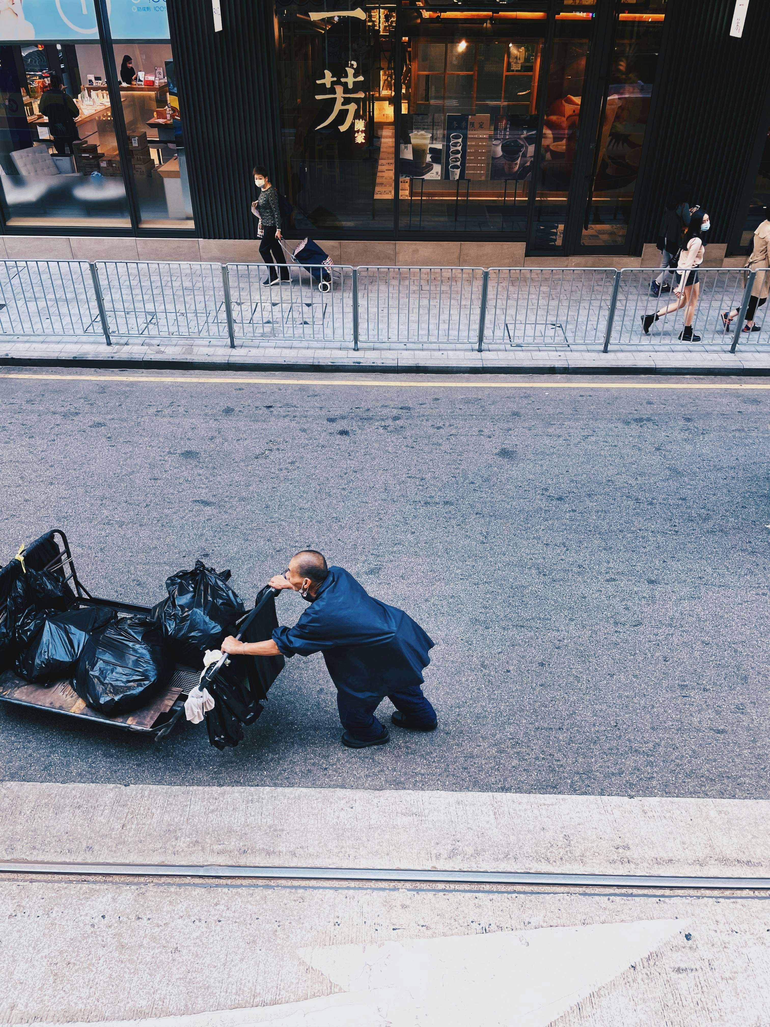 On the Edge of the Street, a Worker with a Cart