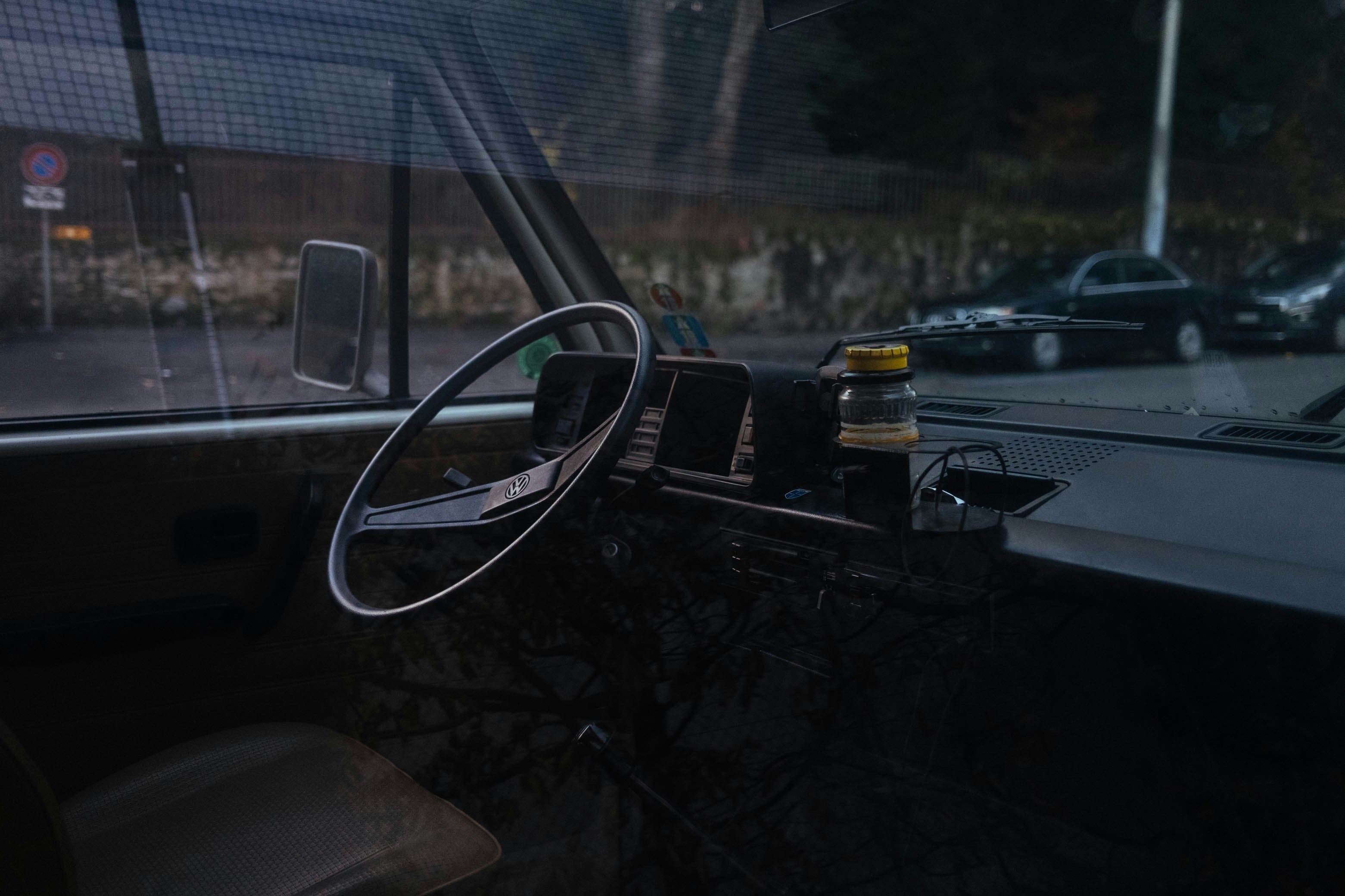 Noir Inside: A Dim Car Cabin with a Lone Bottle on the Dash