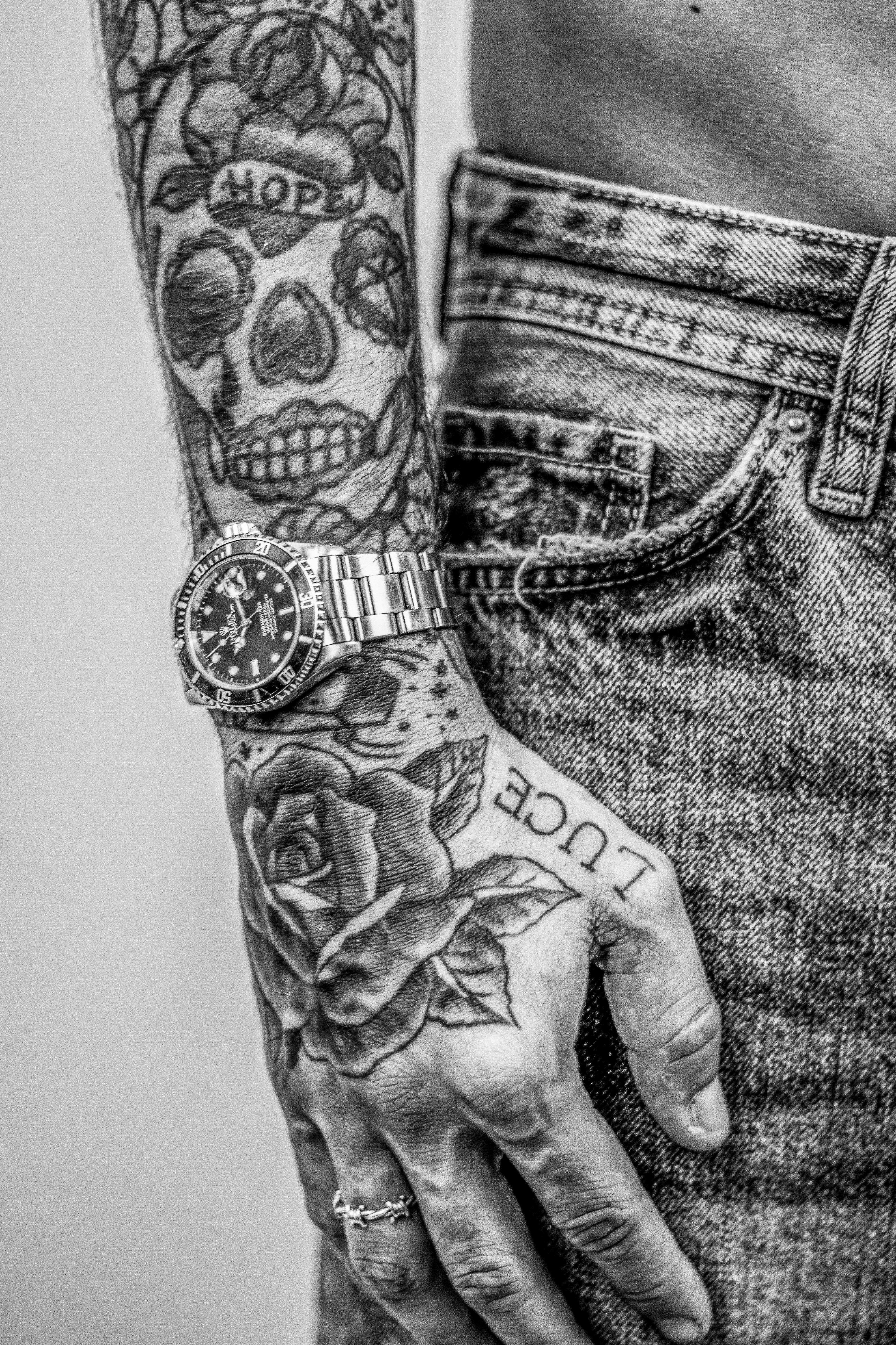 Ink and Steel: A Tattooed Arm Wears Time Against Denim