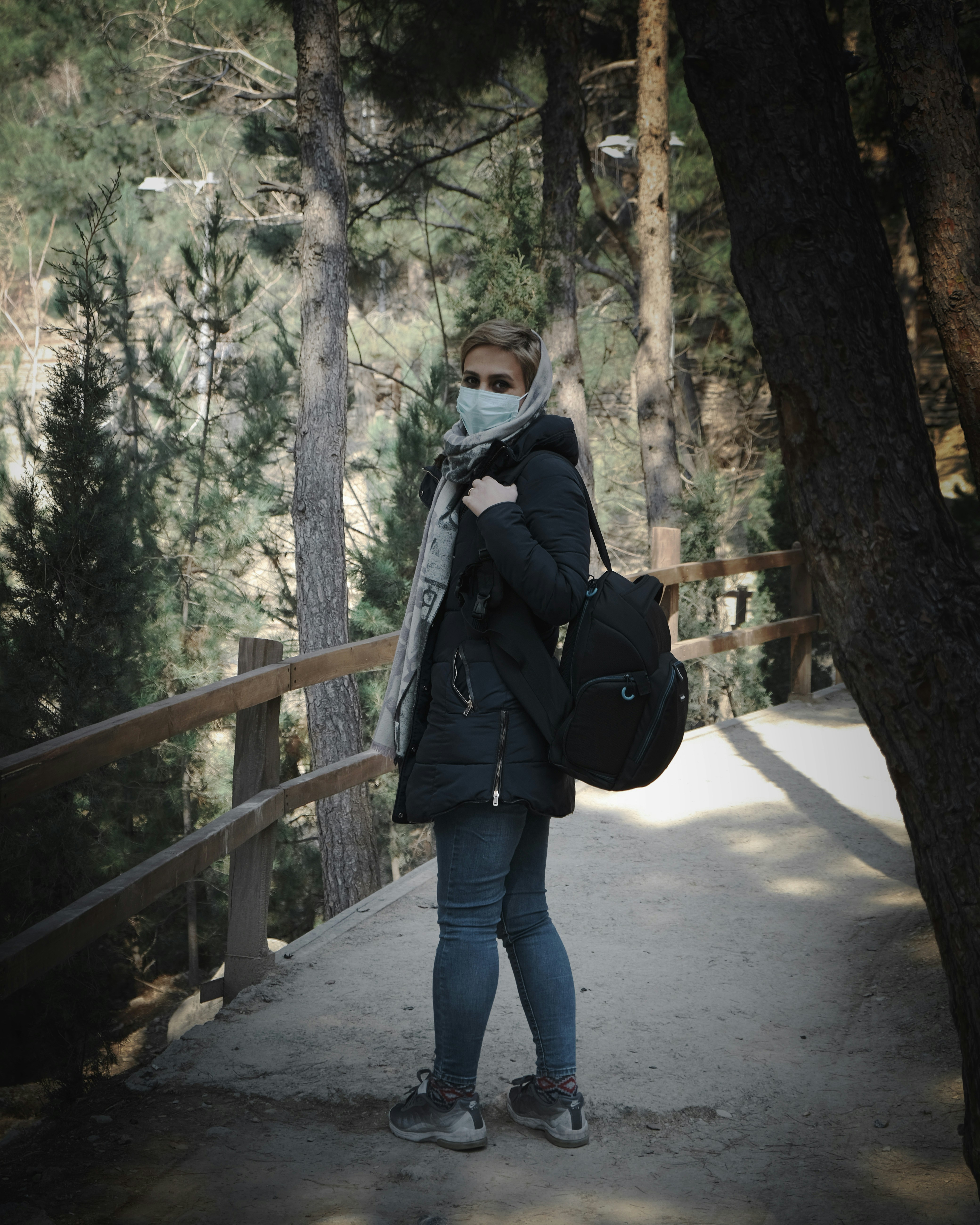 Masked Traveler Pauses Along a Pine-Filled Forest Trail