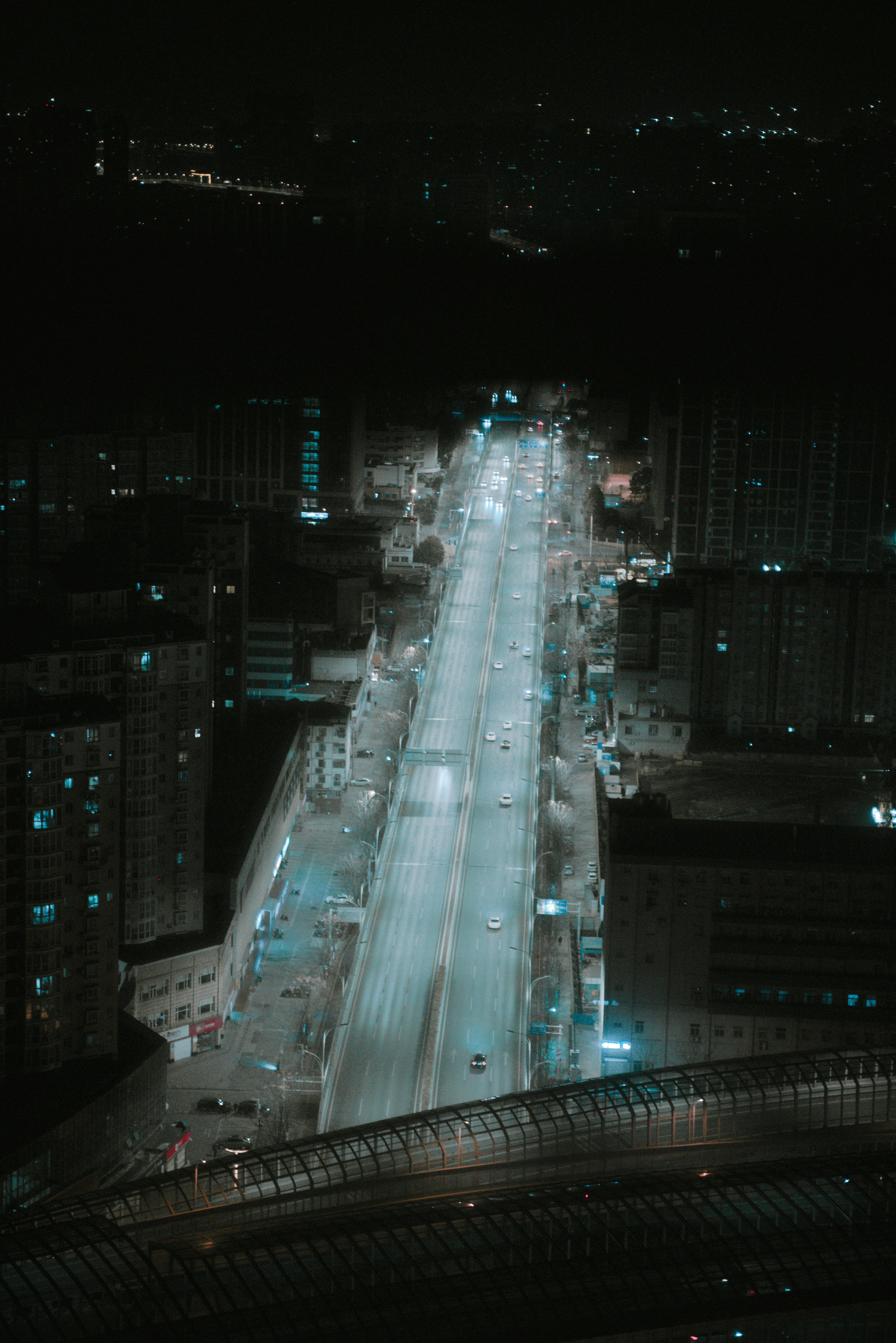 Aerial view of a bustling city road illuminated by streetlights and vehicle headlights at night, showcasing the vibrancy of urban life.