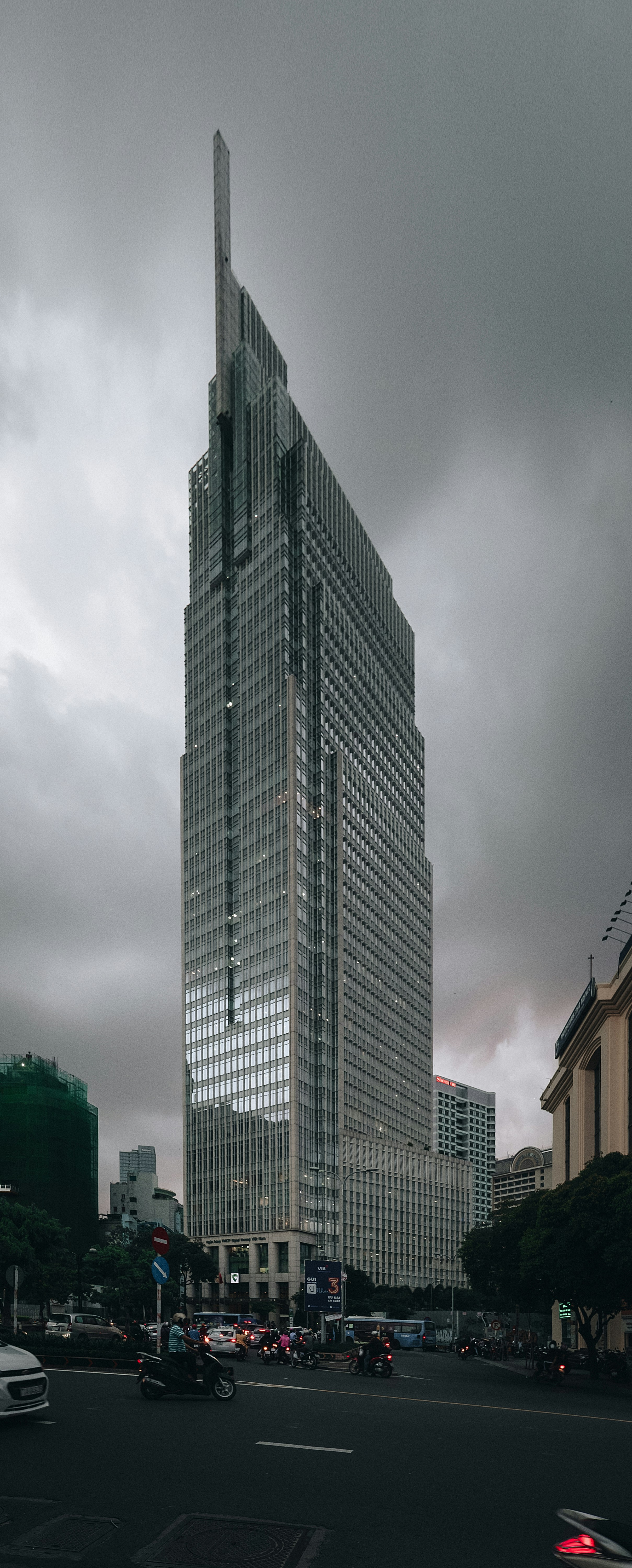 The Glass Needle Rising Over a Grey City Street