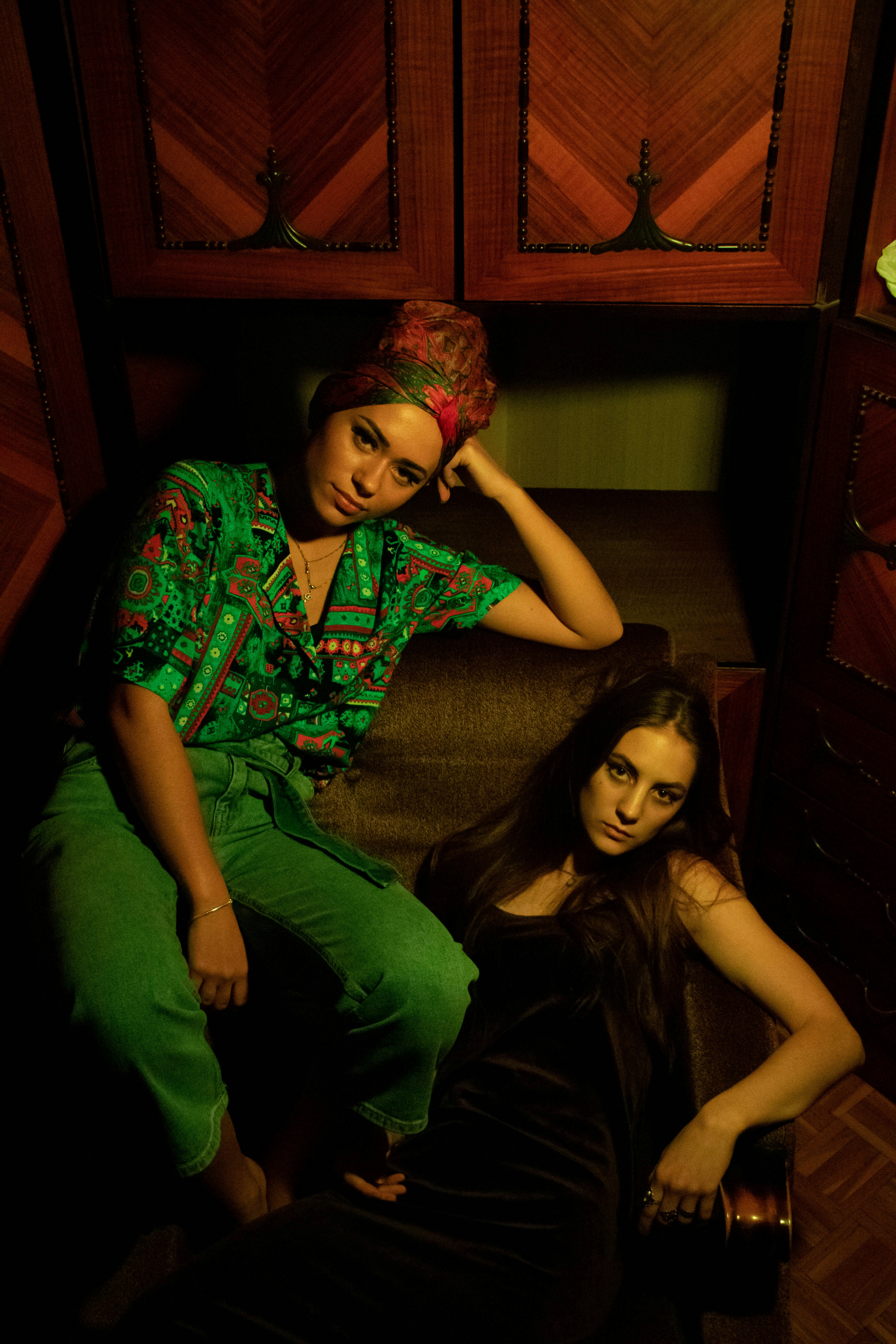 Emerald Threads in Velvet Night: Two Friends Recline on a Vintage Couch