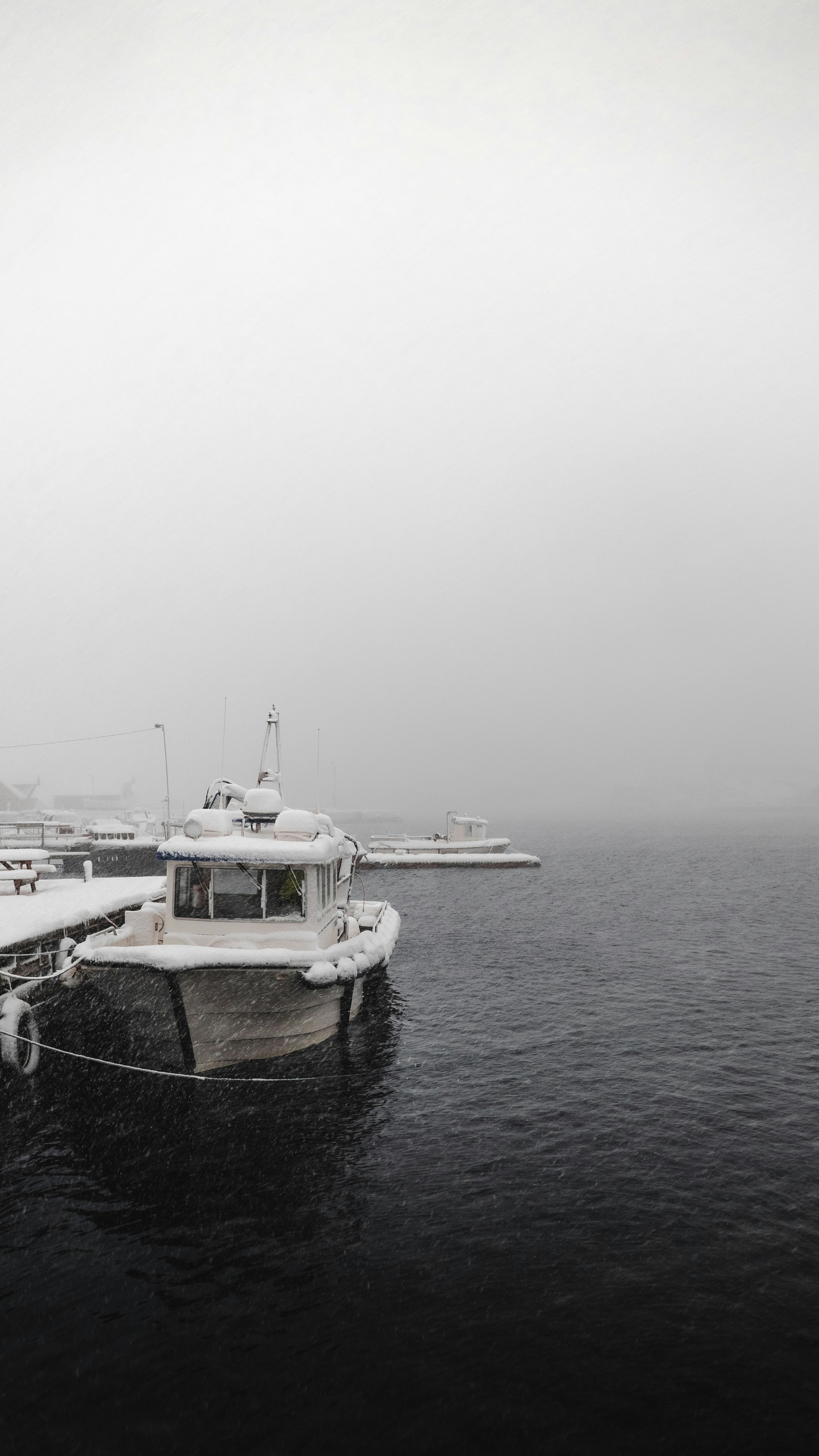 Snowbound Harbor: A Snow-Covered Boat Anchored in Quiet Fog