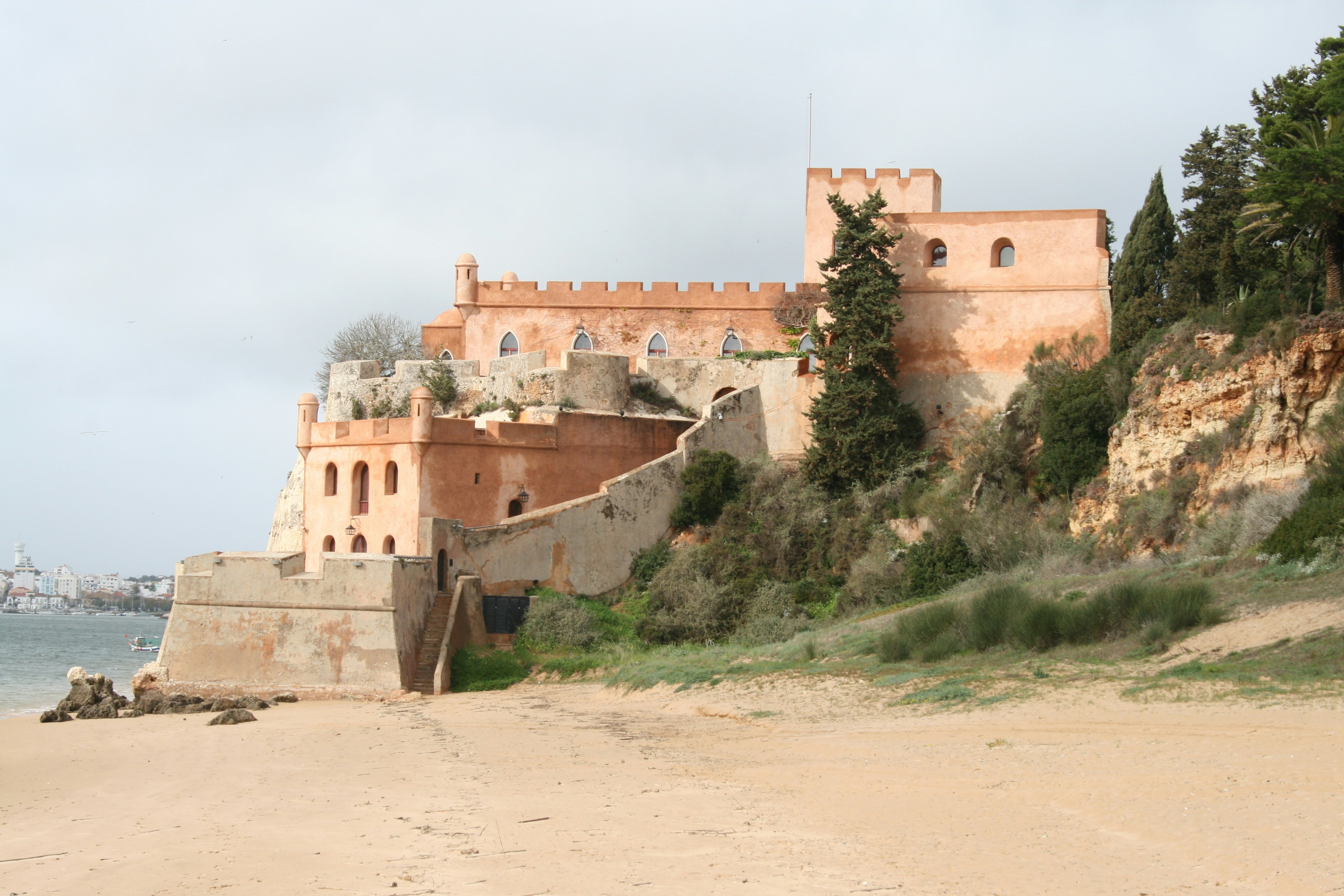Sea-Framed Fortress: Sunlit Bastions Rise Over a Sandy Shore