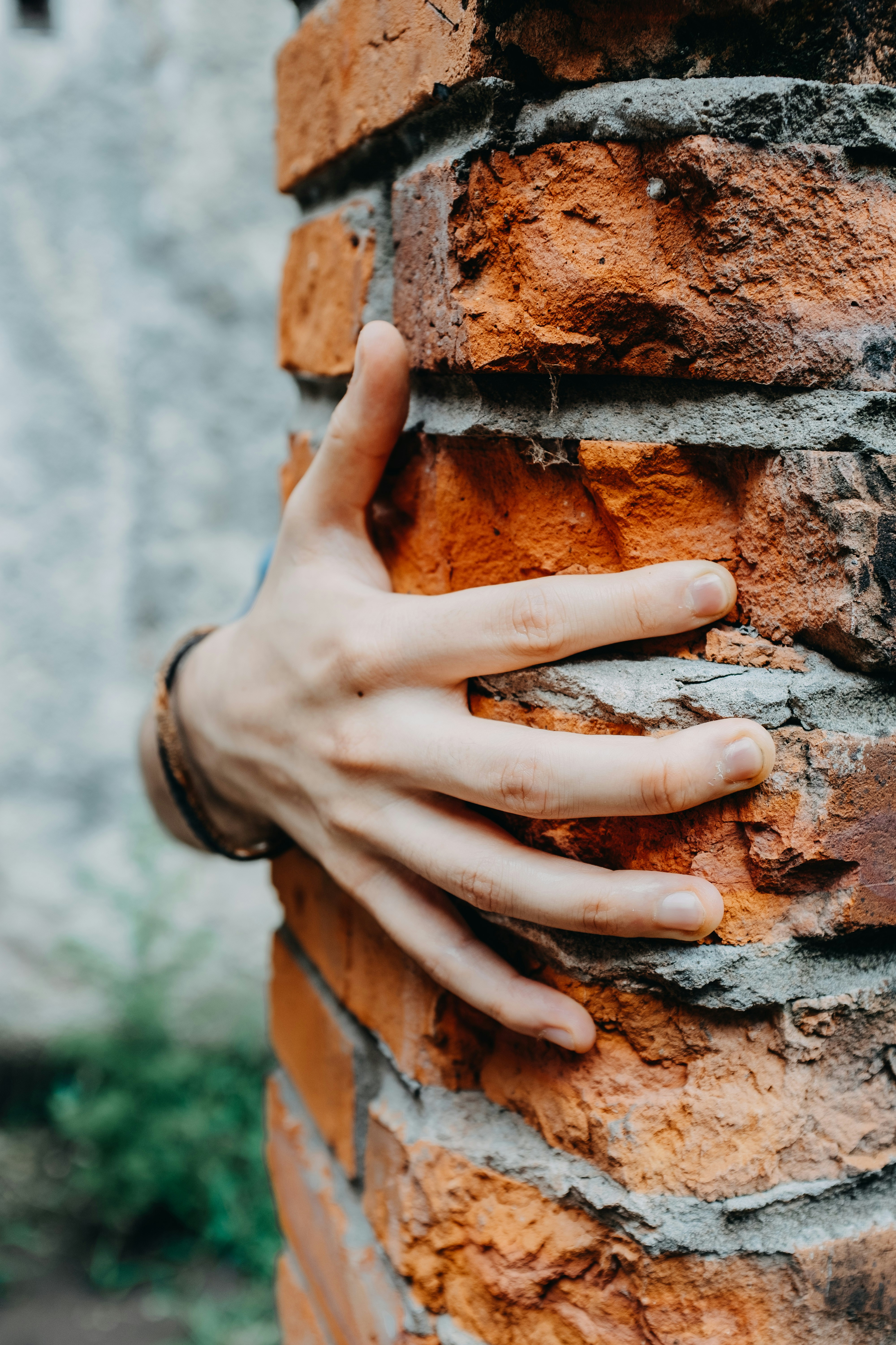 Brick by Grip: A Hand Embracing a Weathered Wall
