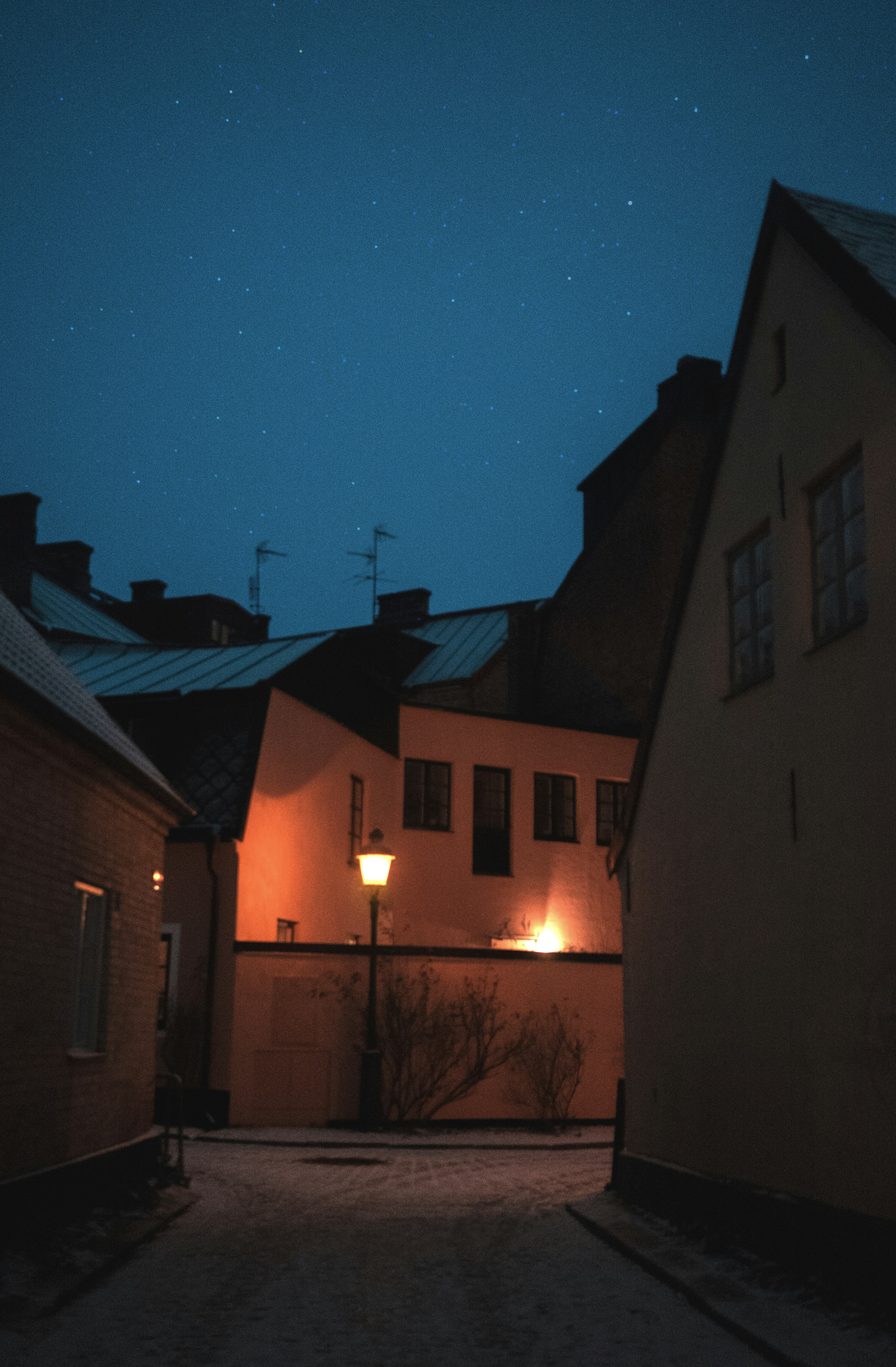 Orange glow in the alley: a quiet nocturne beneath a starry sky