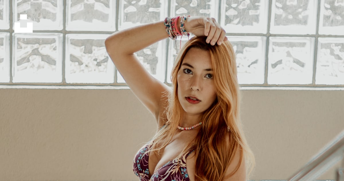 白い金属の手すりに座っている青と白の花柄のビキニを着た女性の写真 Unsplashのカジュエイロの無料画像